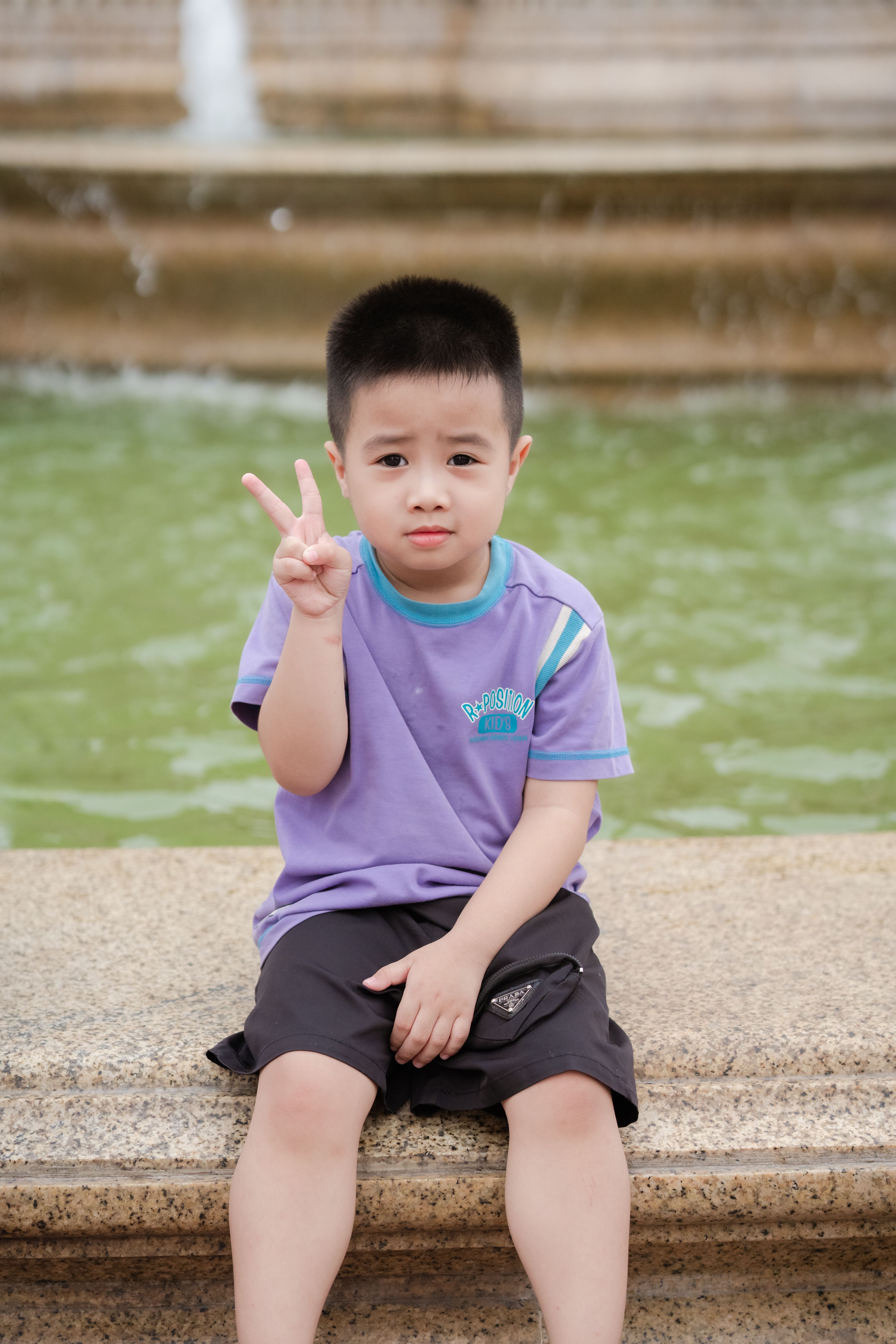 Portrait of a Boy Sitting by the Fountain, showing a Peace Sign · Free ...