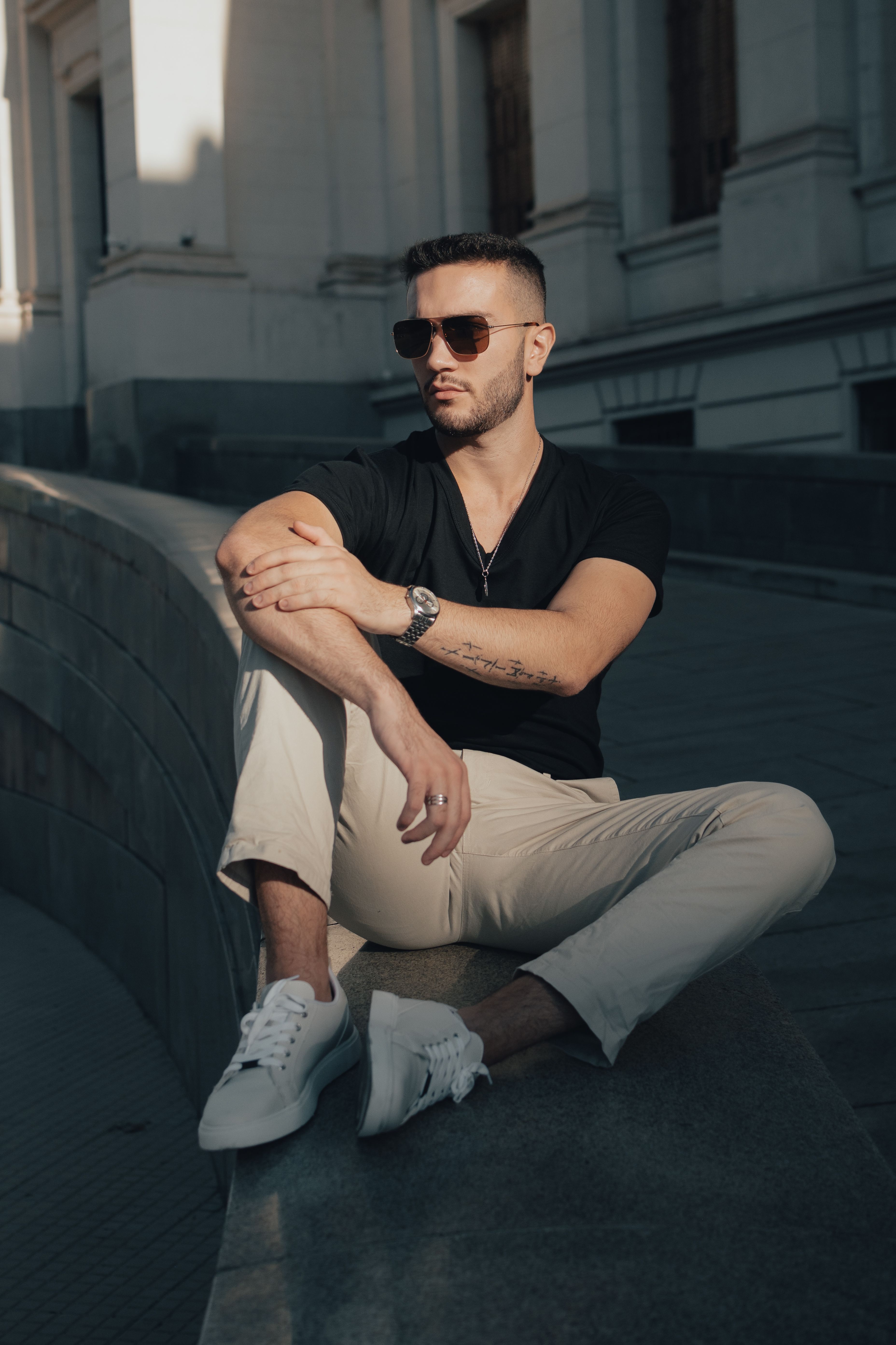 A man sitting on a ledge wearing white sneakers · Free Stock Photo