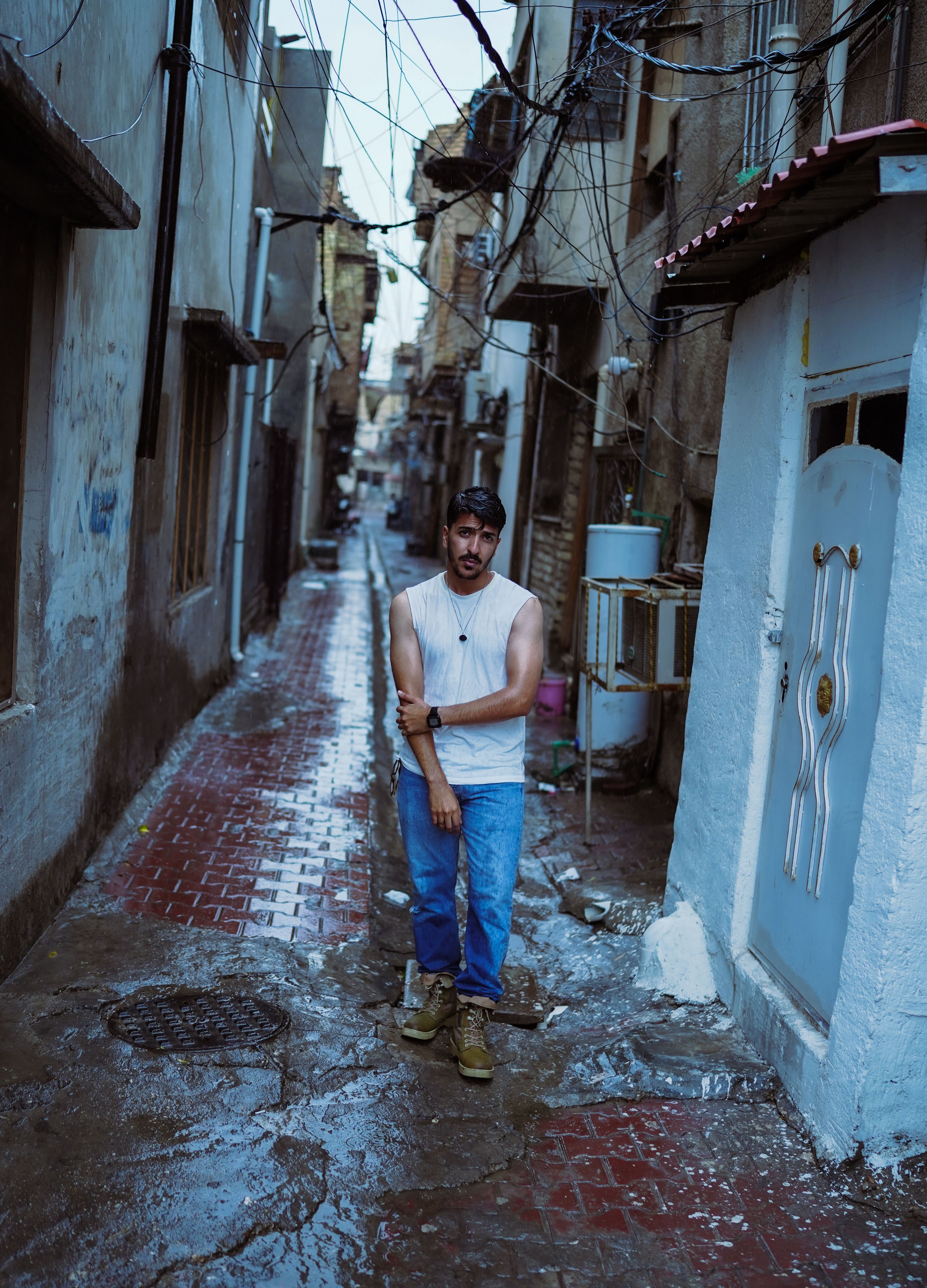A man standing in a narrow alleyway with a baseball bat · Free Stock Photo