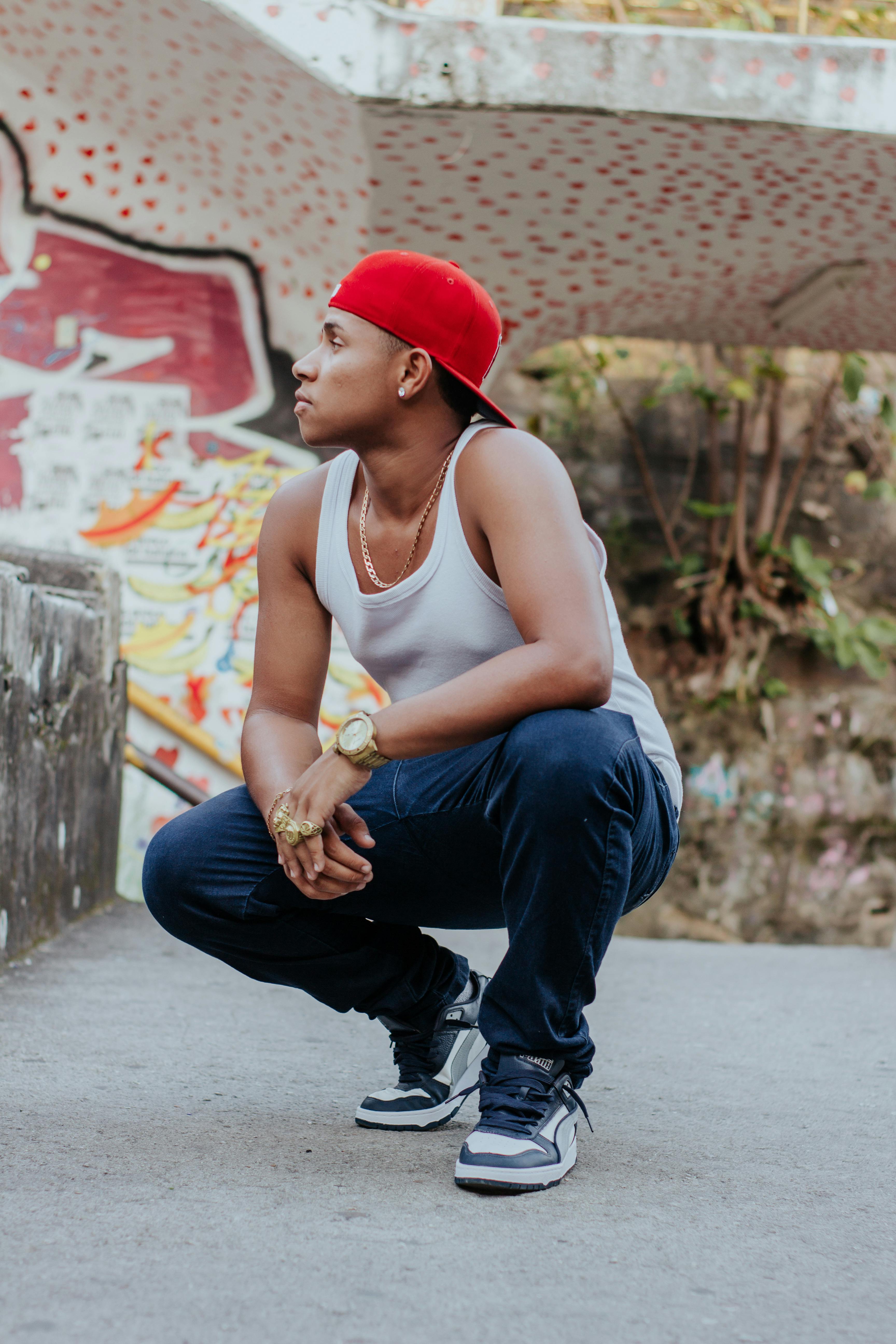 A Man in Casual Clothing Crouching near a Wall with Graffiti · Free ...
