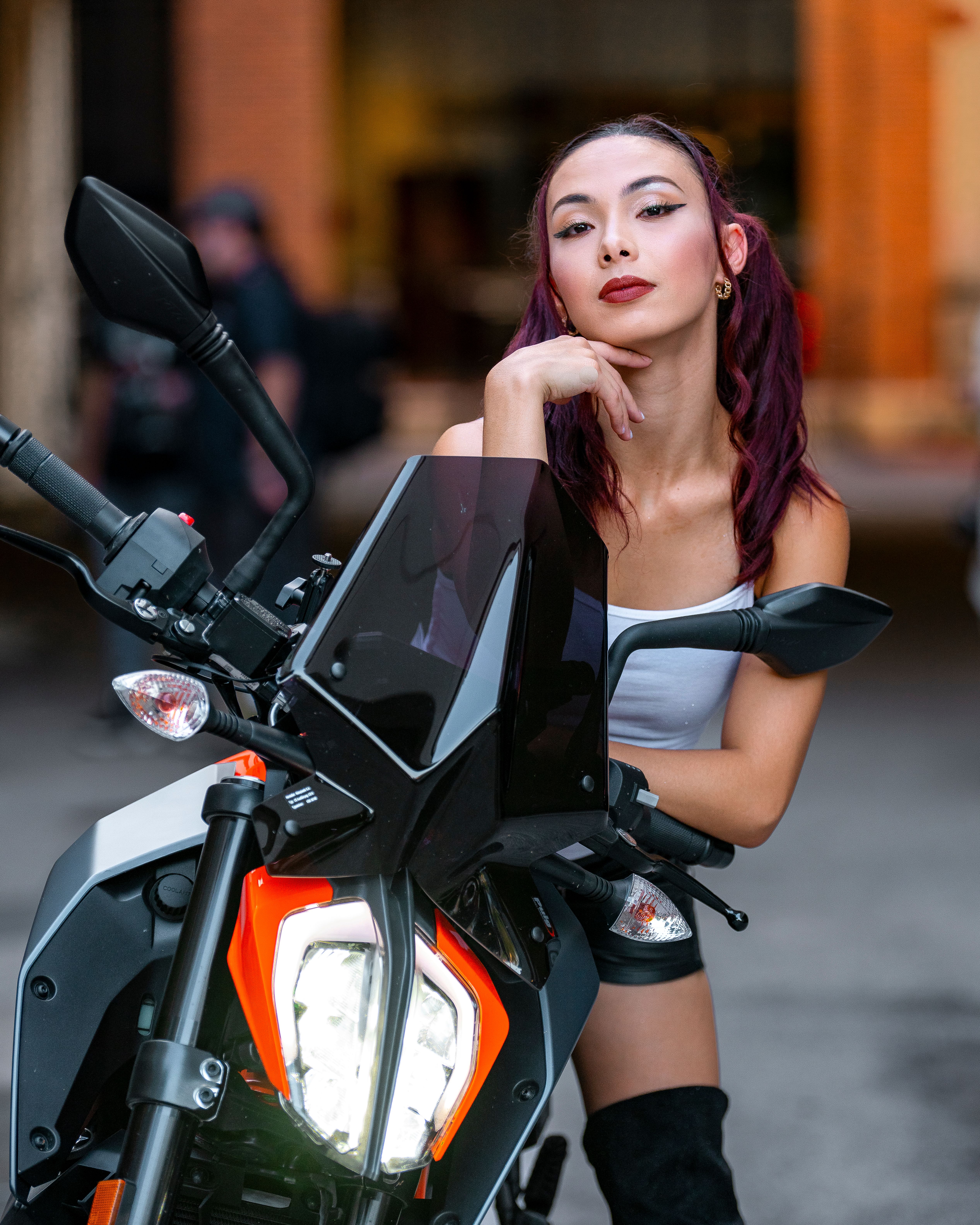 Portrait of an Attractive Woman standing by a Motorcycle · Free Stock Photo