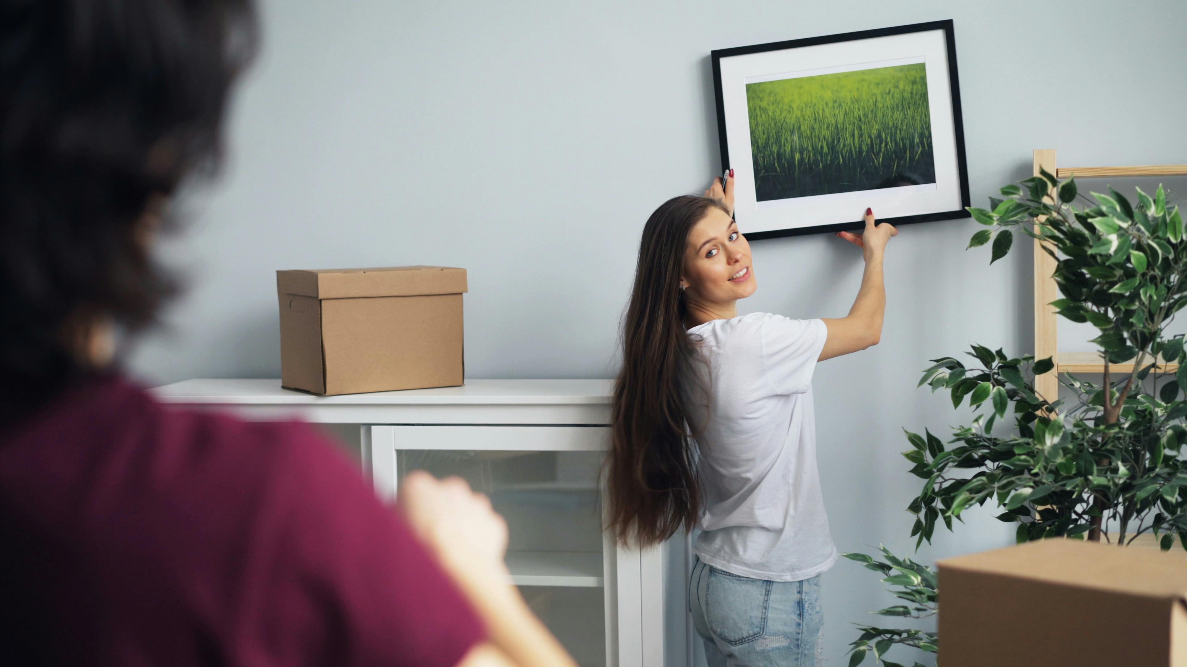 Woman Putting Picture on Wall · Free Stock Photo