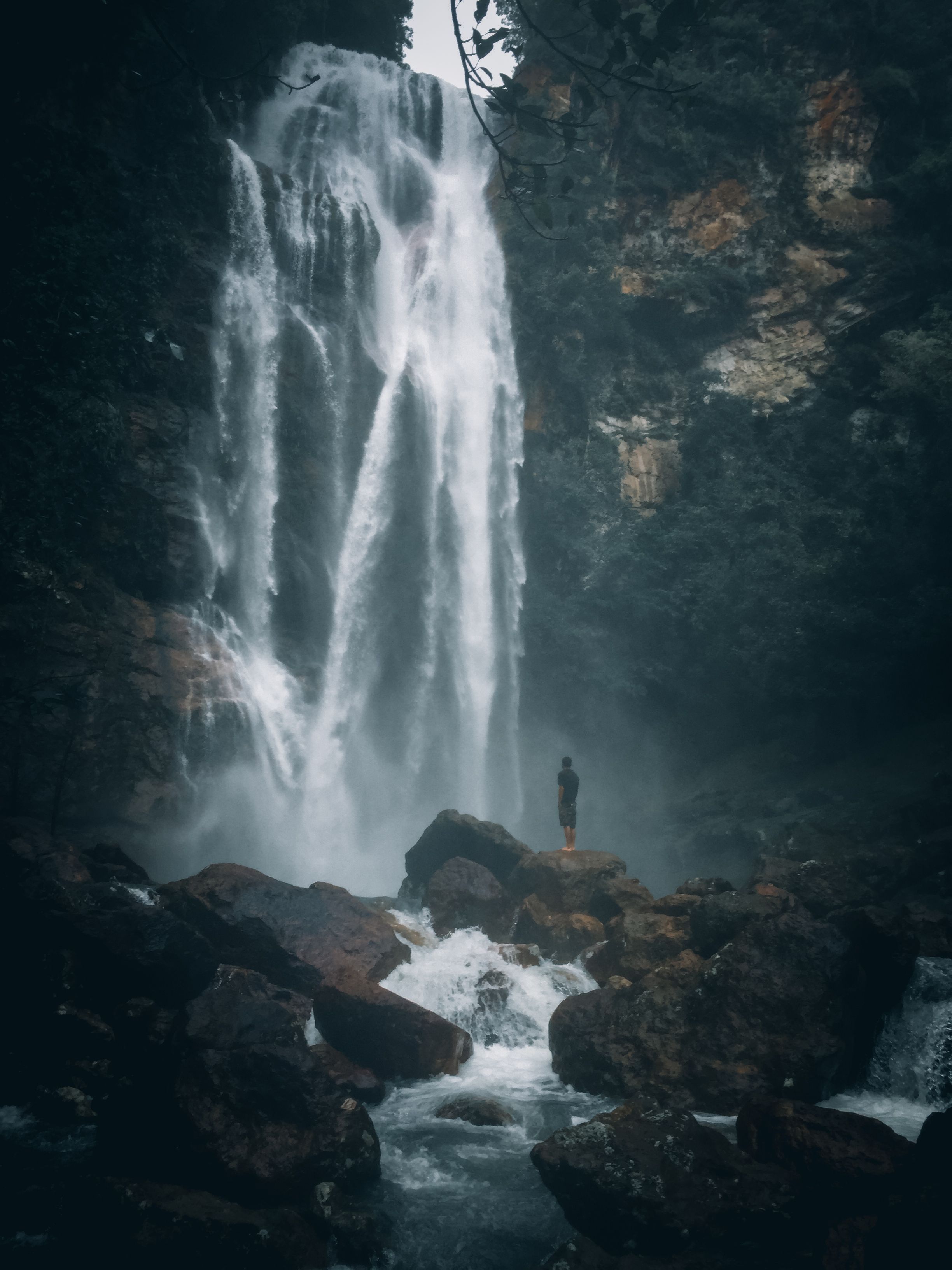 A person standing in front of a waterfall · Free Stock Photo