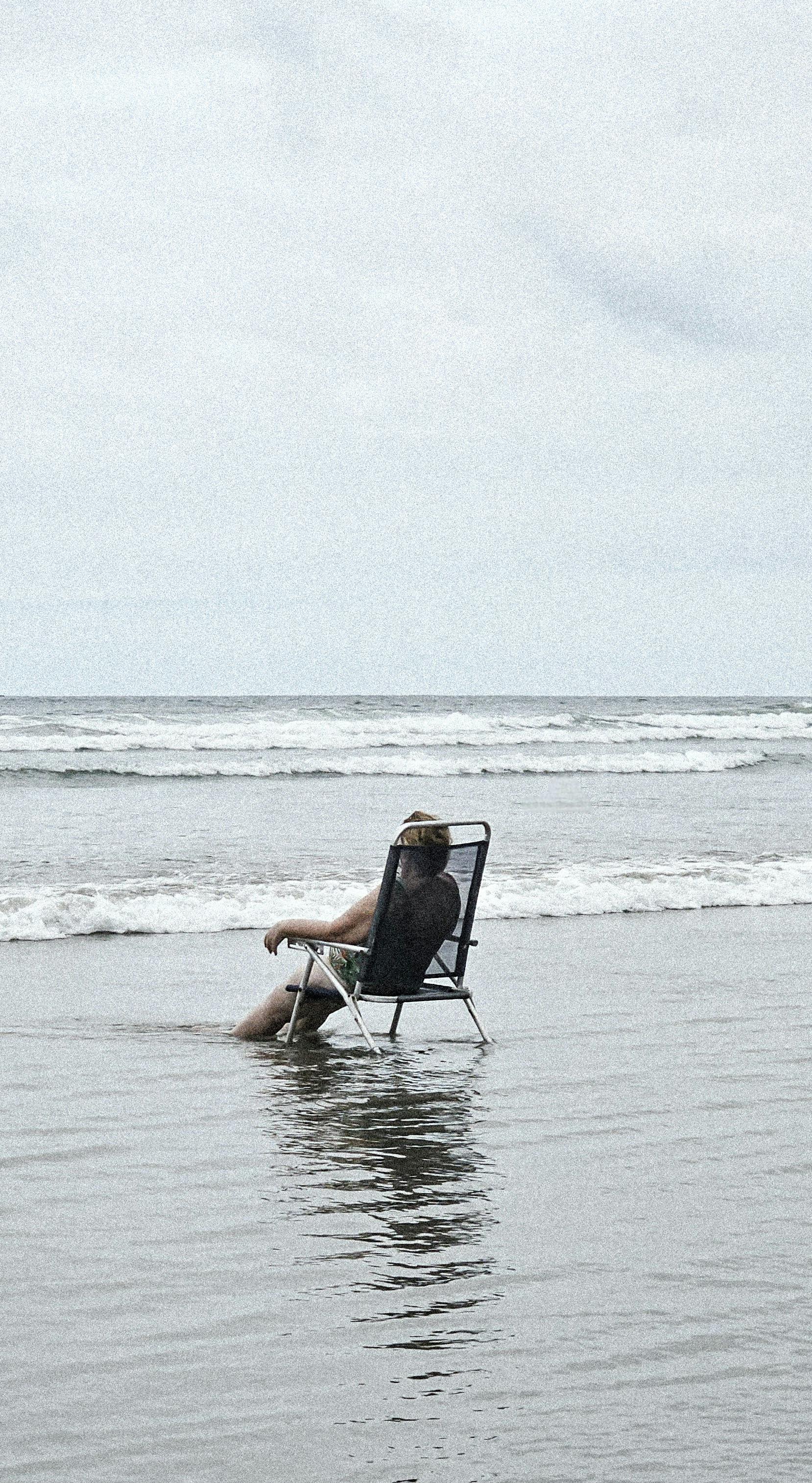 Rear View of a Man Sitting in a Lounge Chair in the Sea · Free Stock Photo