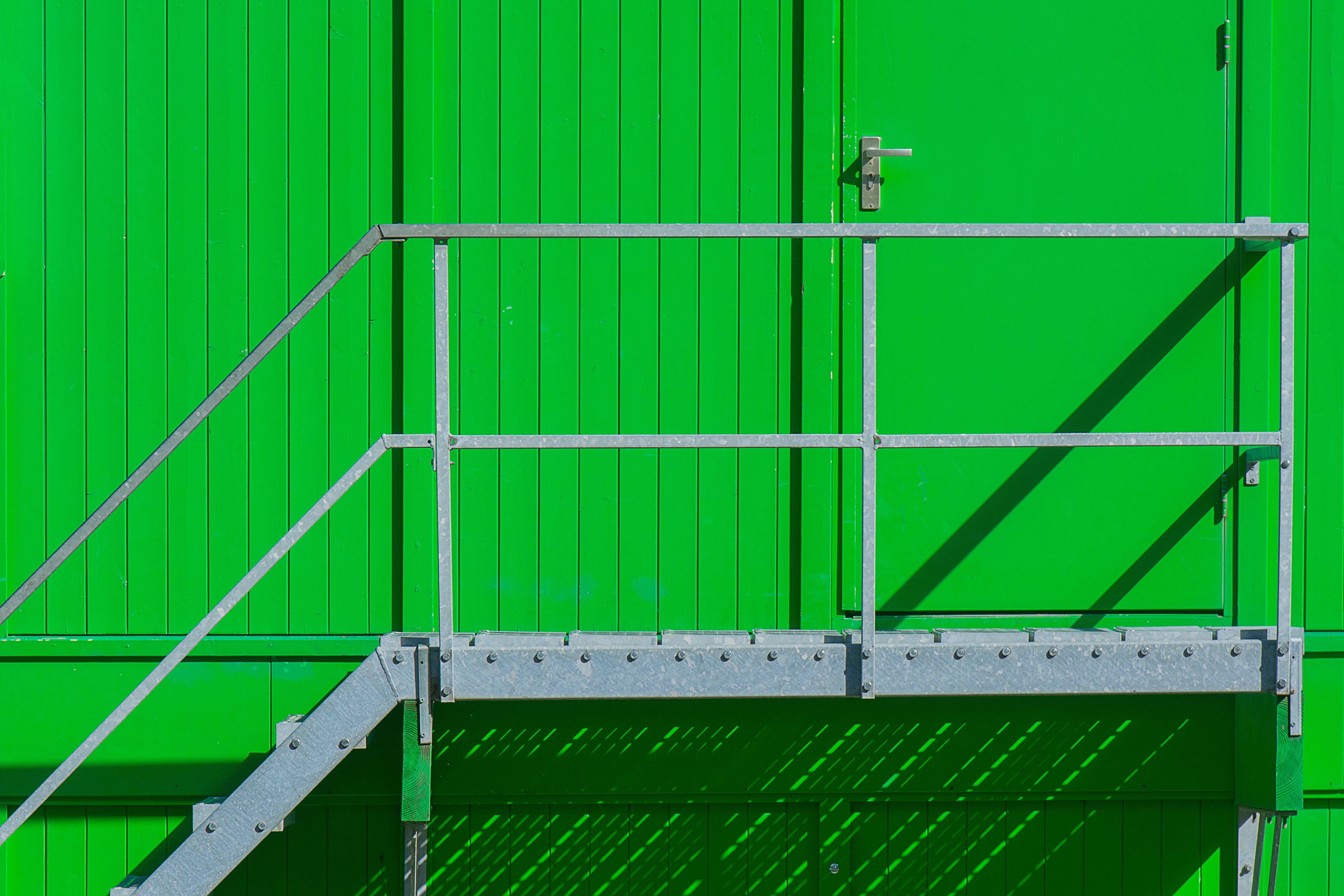 A green building with stairs and a metal railing · Free Stock Photo