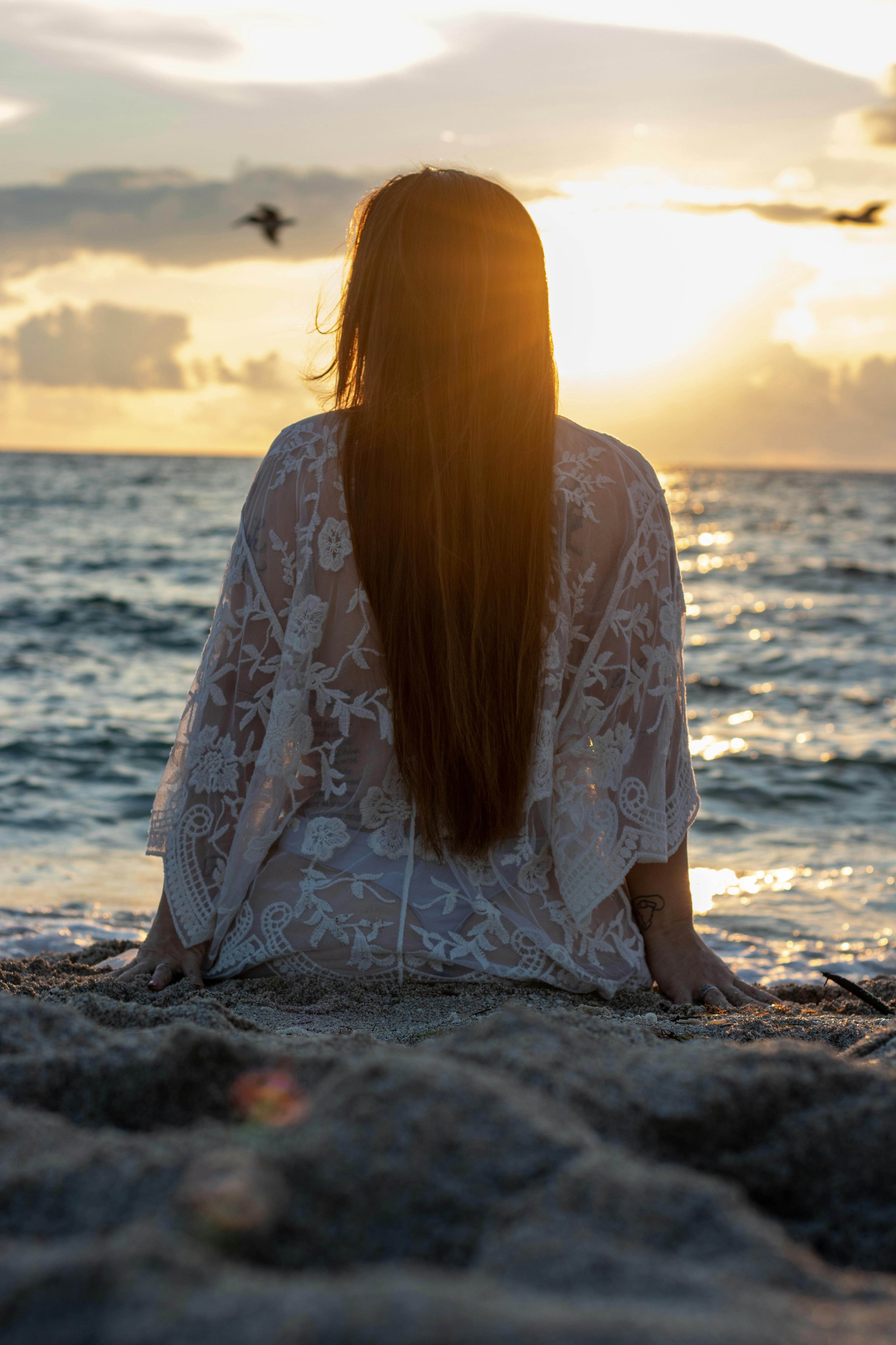 Back View of a Woman Sitting on a Beach · Free Stock Photo