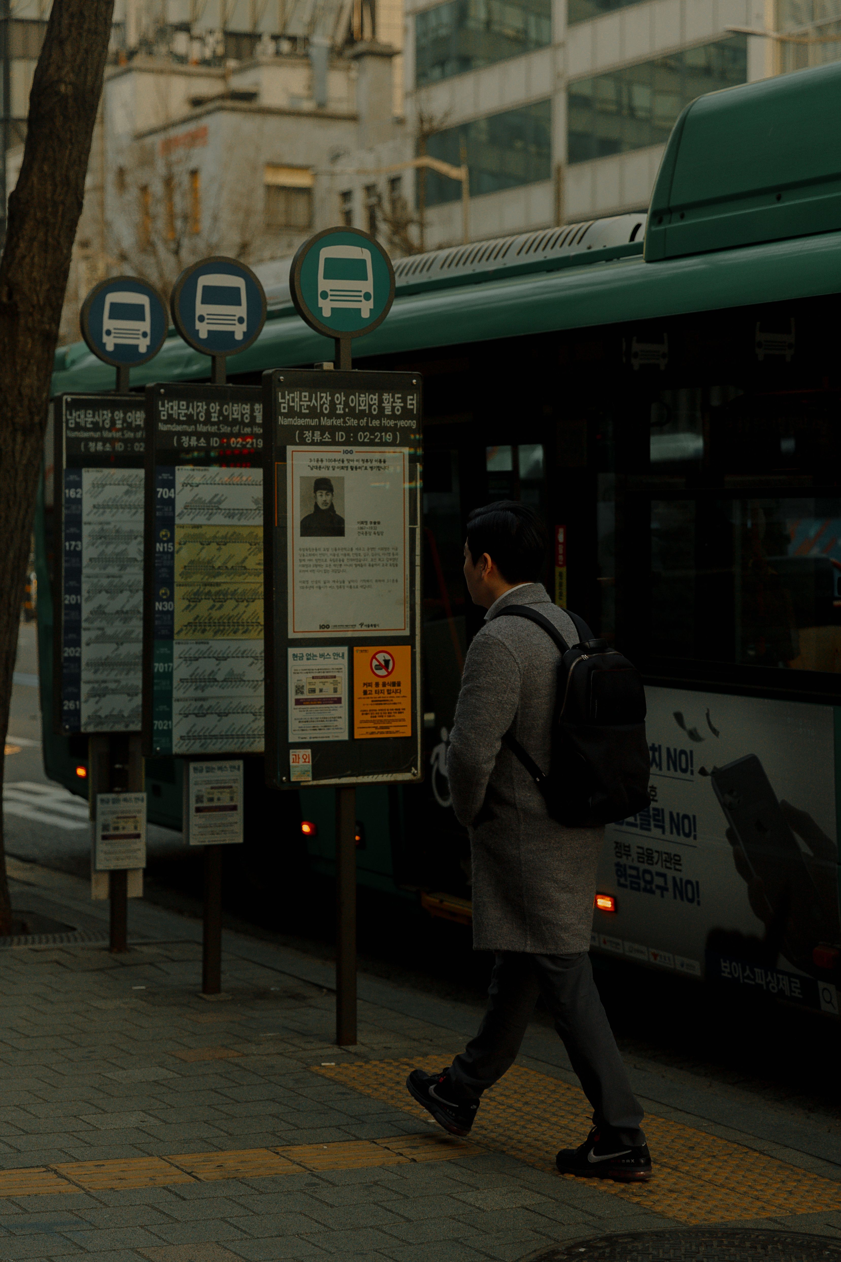 A man walking down the street next to a bus · Free Stock Photo
