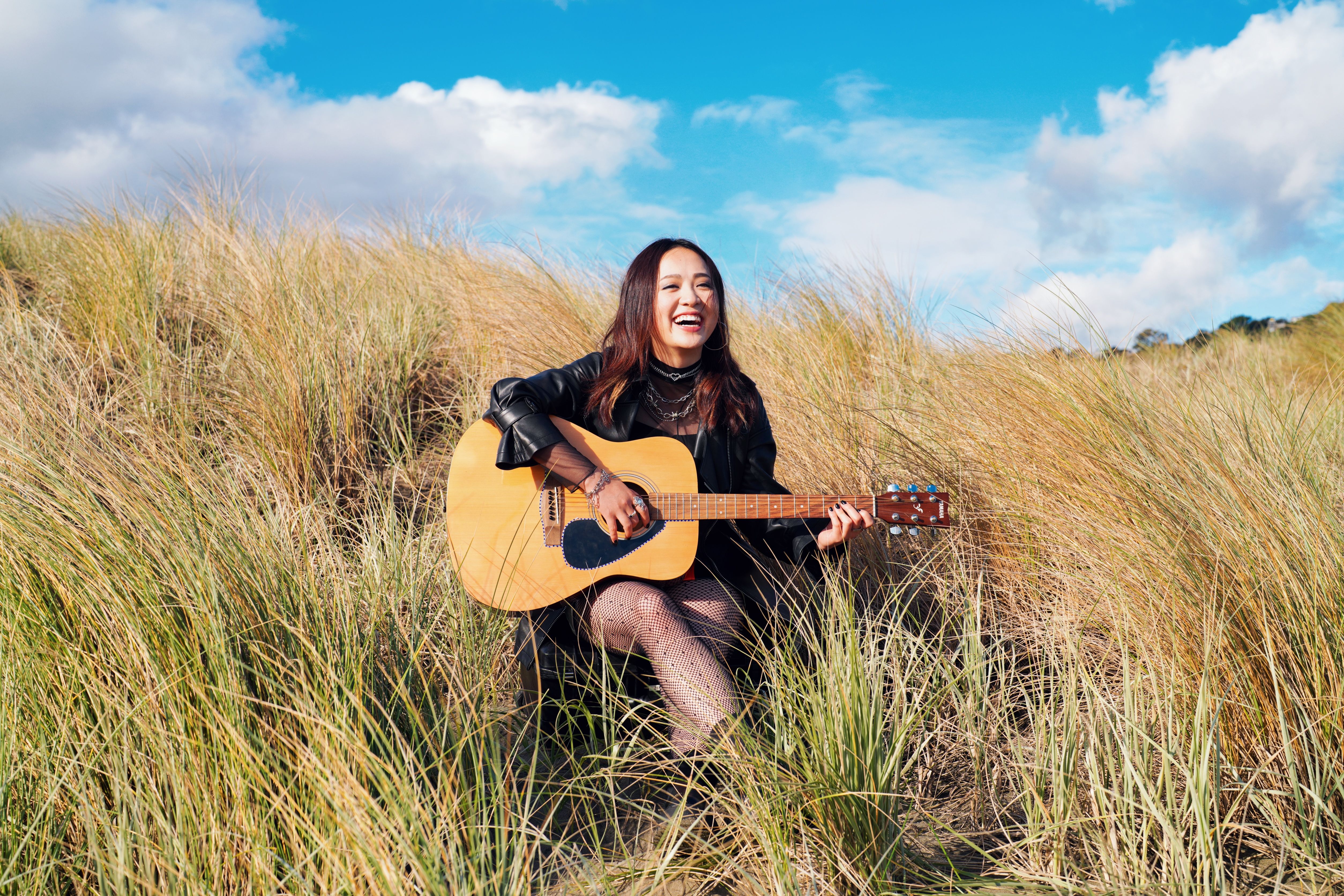 Laughing Woman Playing Guitar Sitting in Tall Grass on Hillside · Free ...