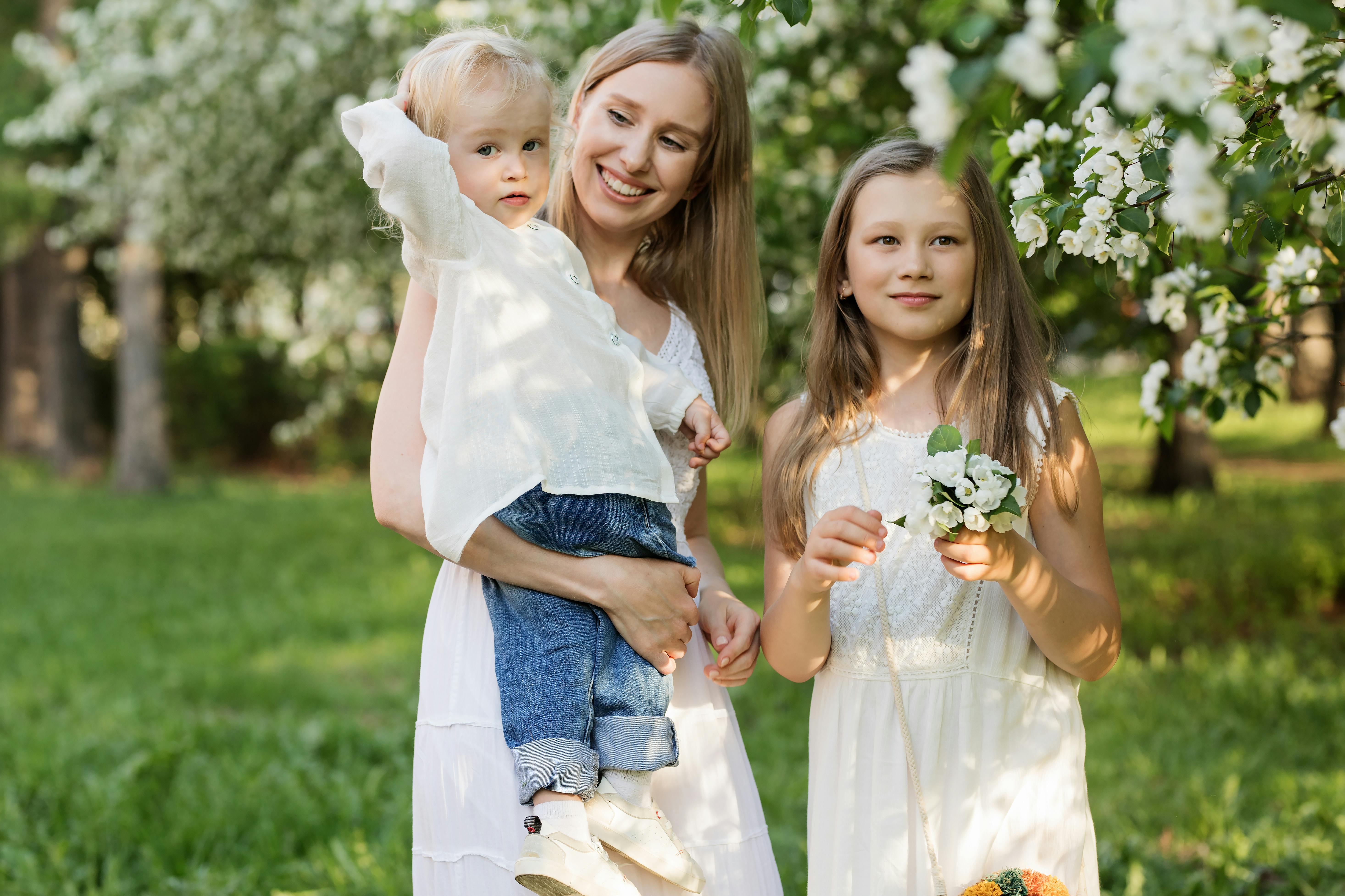 Woman Carrying Child in Carrier While Standing Beside Girl · Free Stock ...