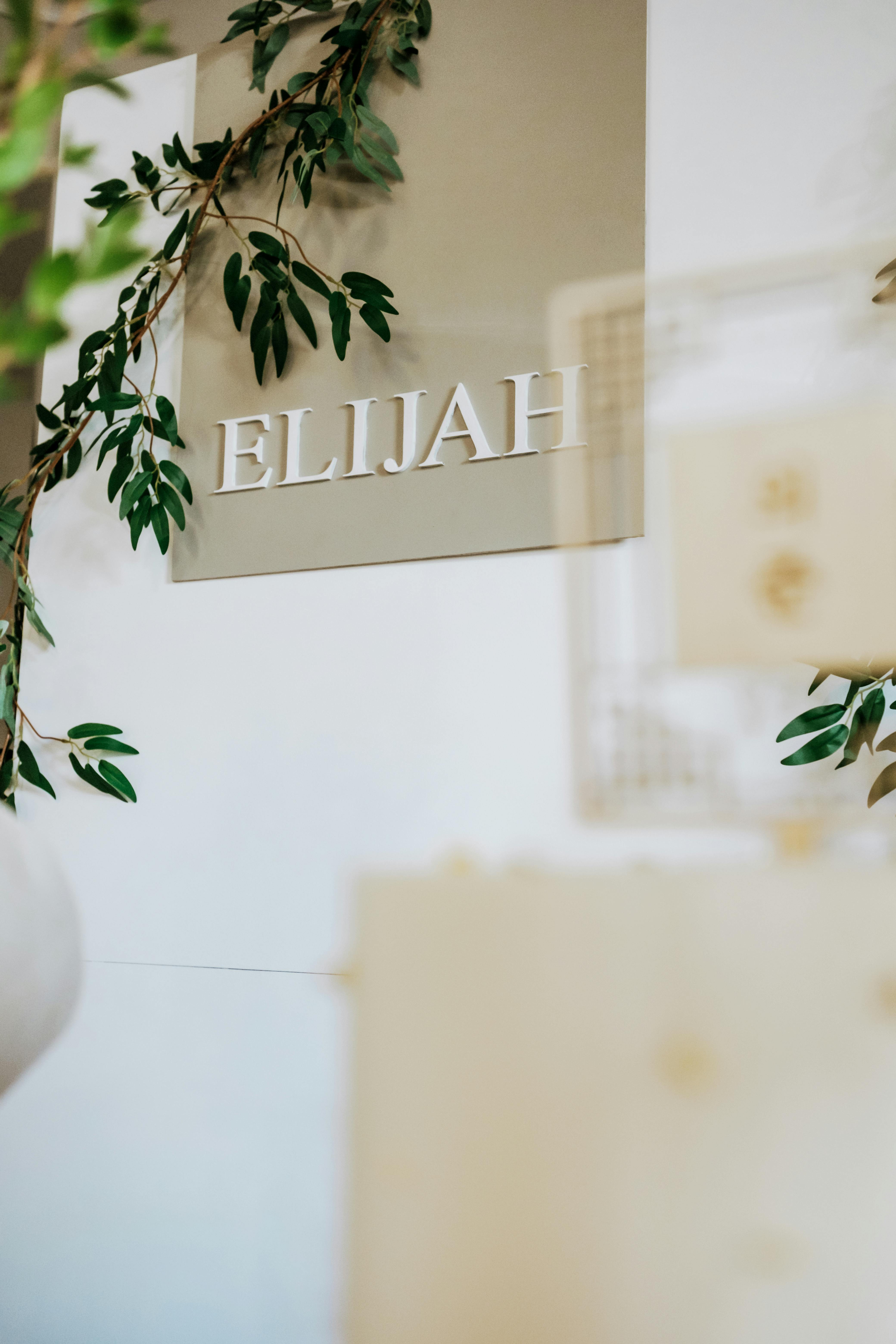 A sign that says elijah with plants in front of it · Free Stock Photo