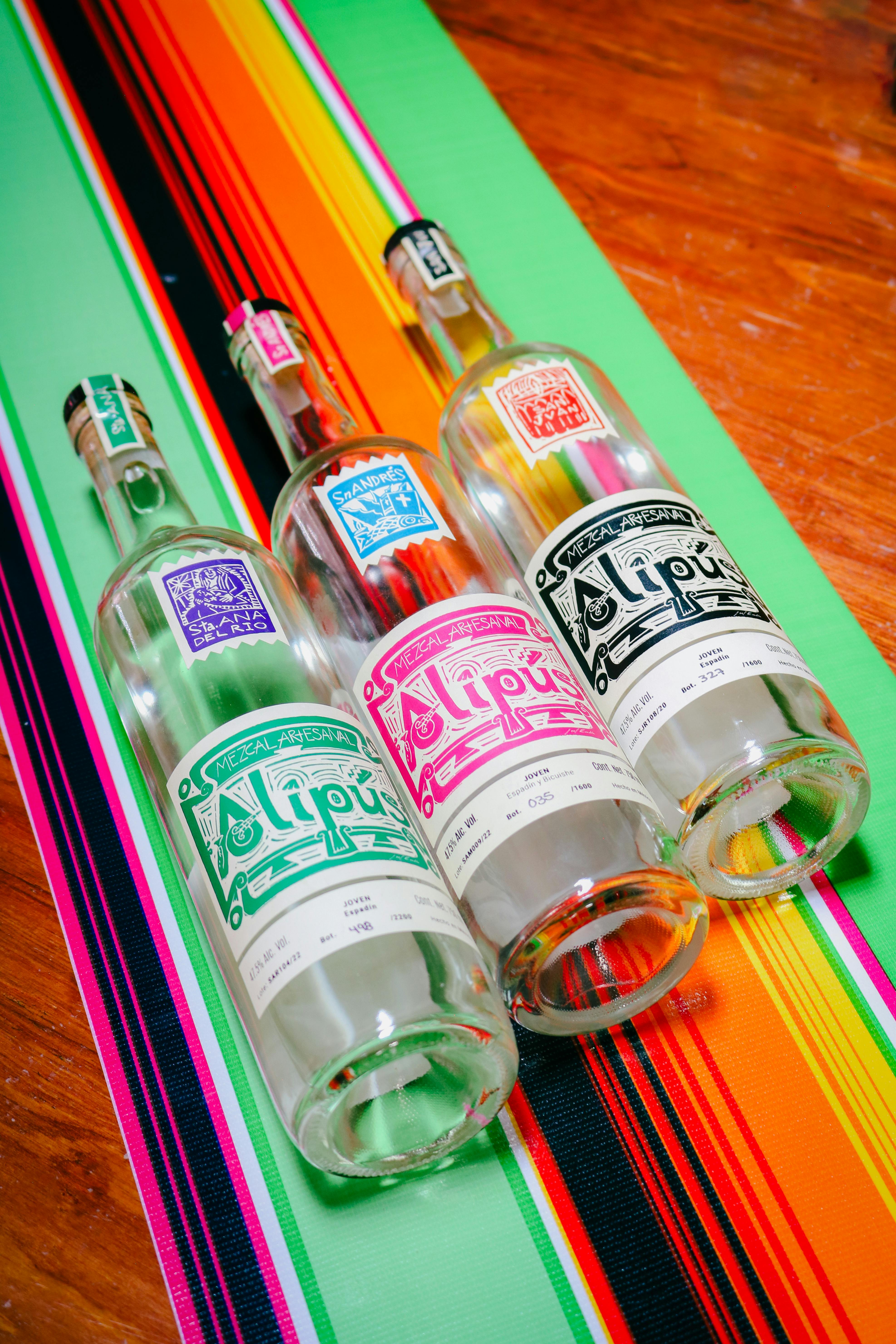 Three bottles of mexican liquor sit on a colorful striped table · Free ...