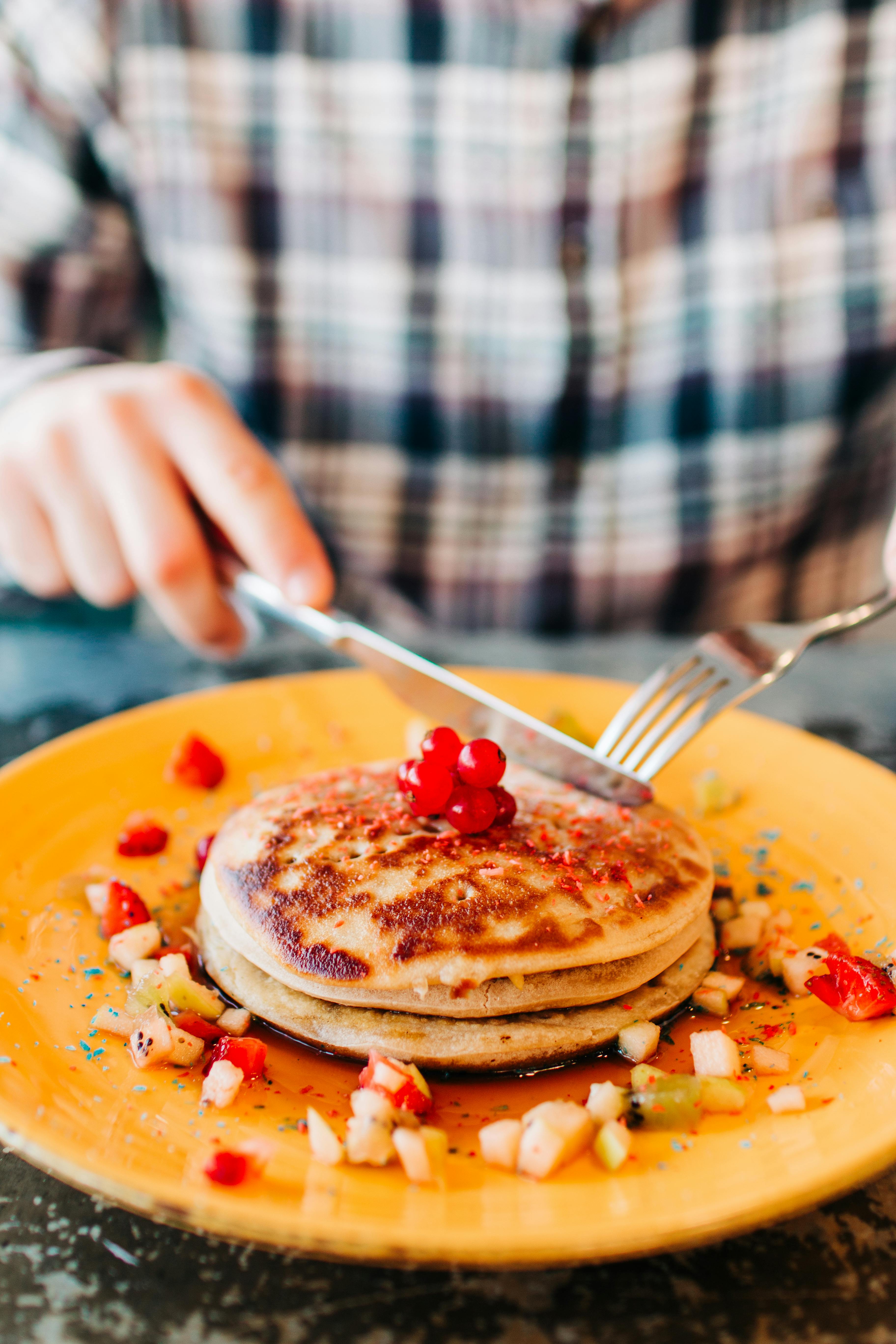 Person Eating Pancakes with Fork and Knife · Free Stock Photo