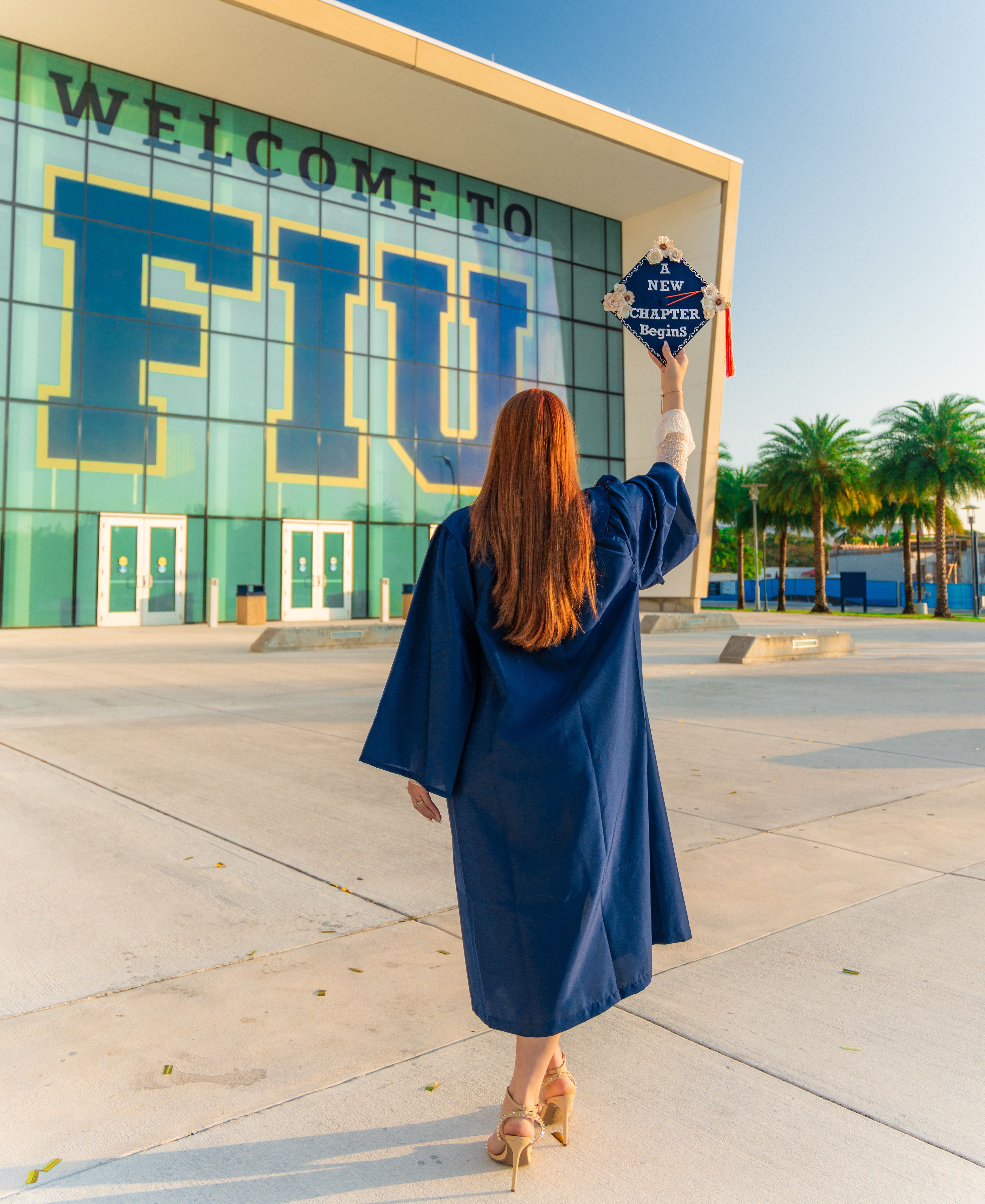 Woman in Graduation Gown Holding Academic Hat in Raised Arm near ...