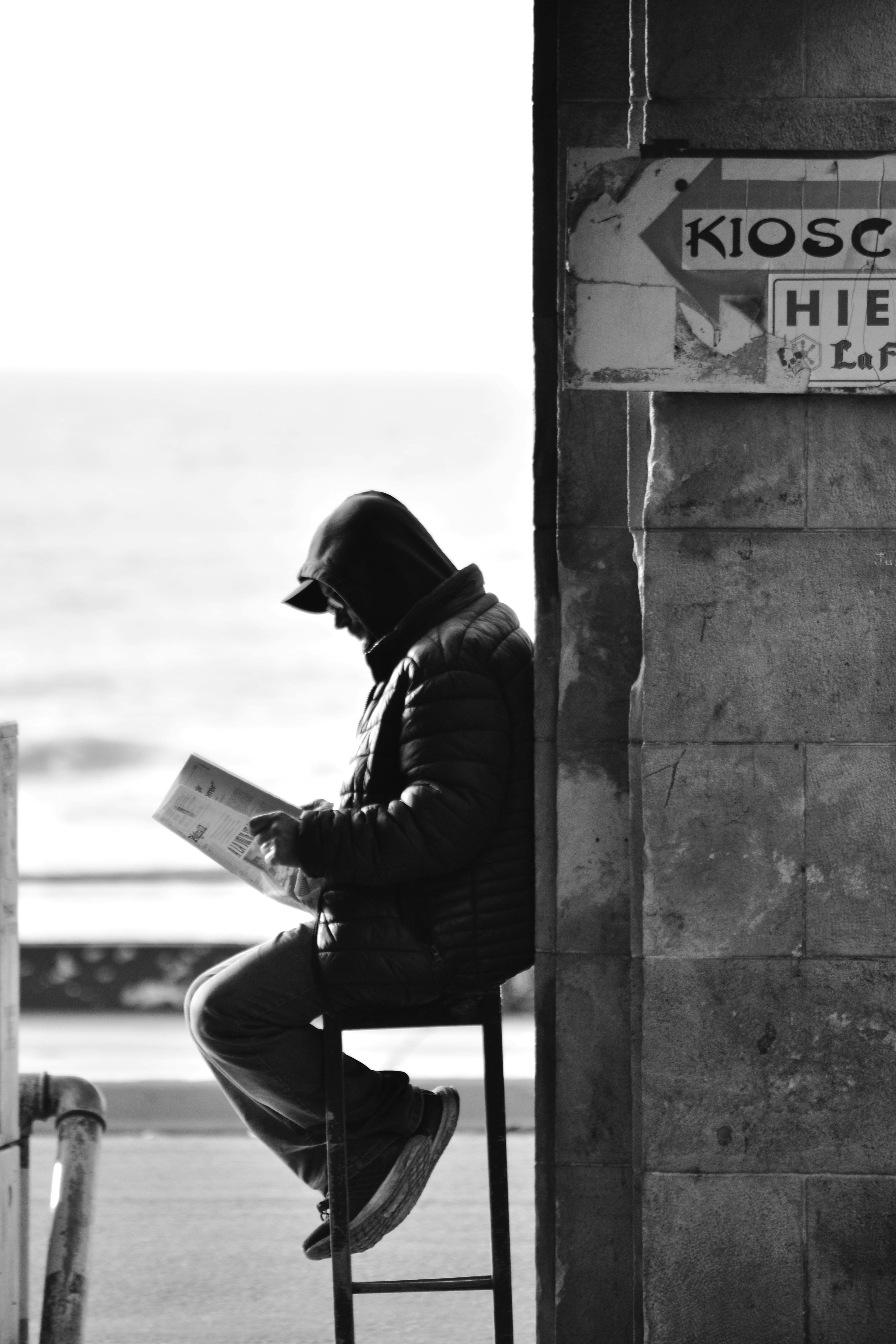 Man Reading Newspaper Sitting on Stool on Sidewalk · Free Stock Photo