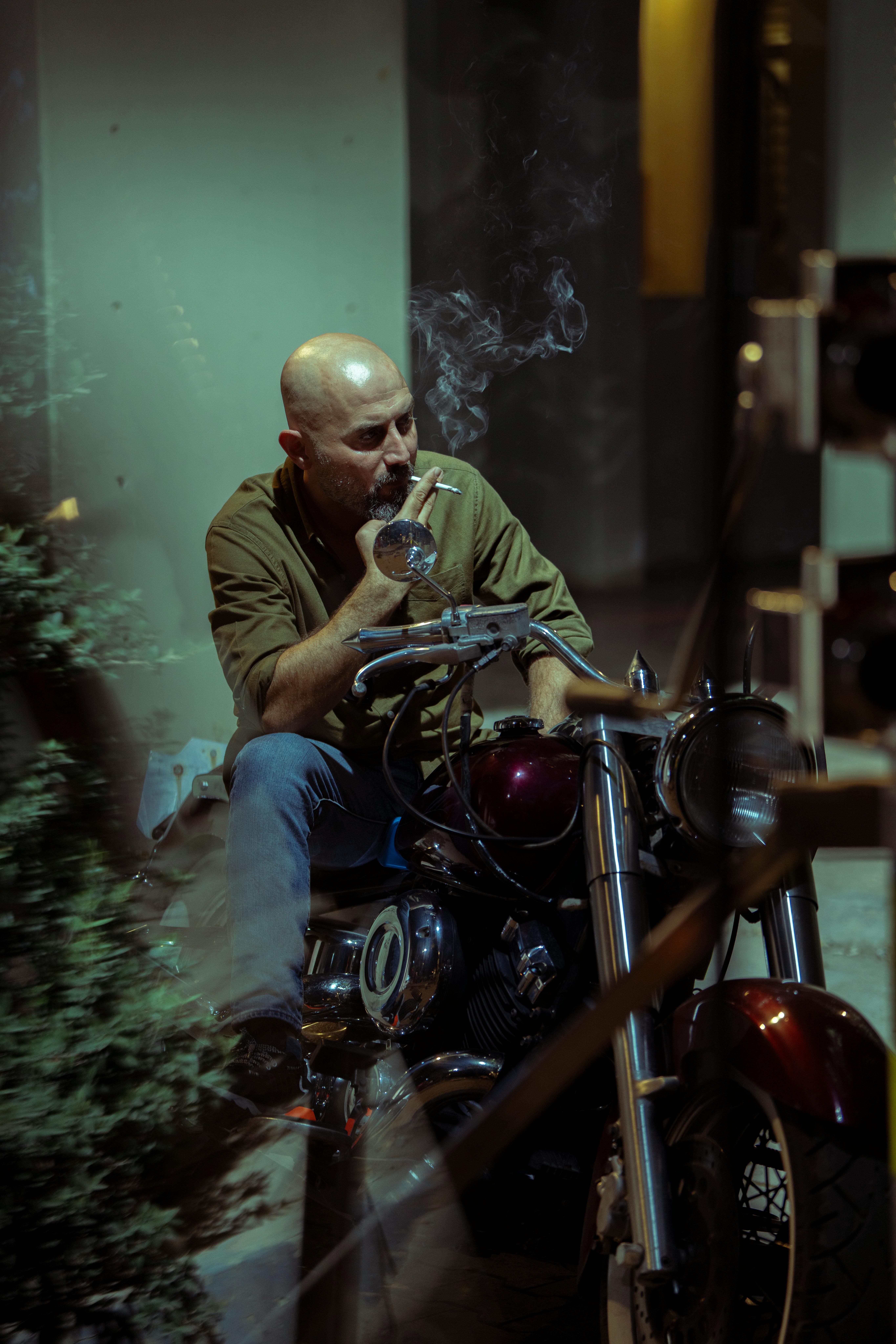 A Bald Man Sitting on a Motorcycle and Smoking a Cigarette · Free Stock ...