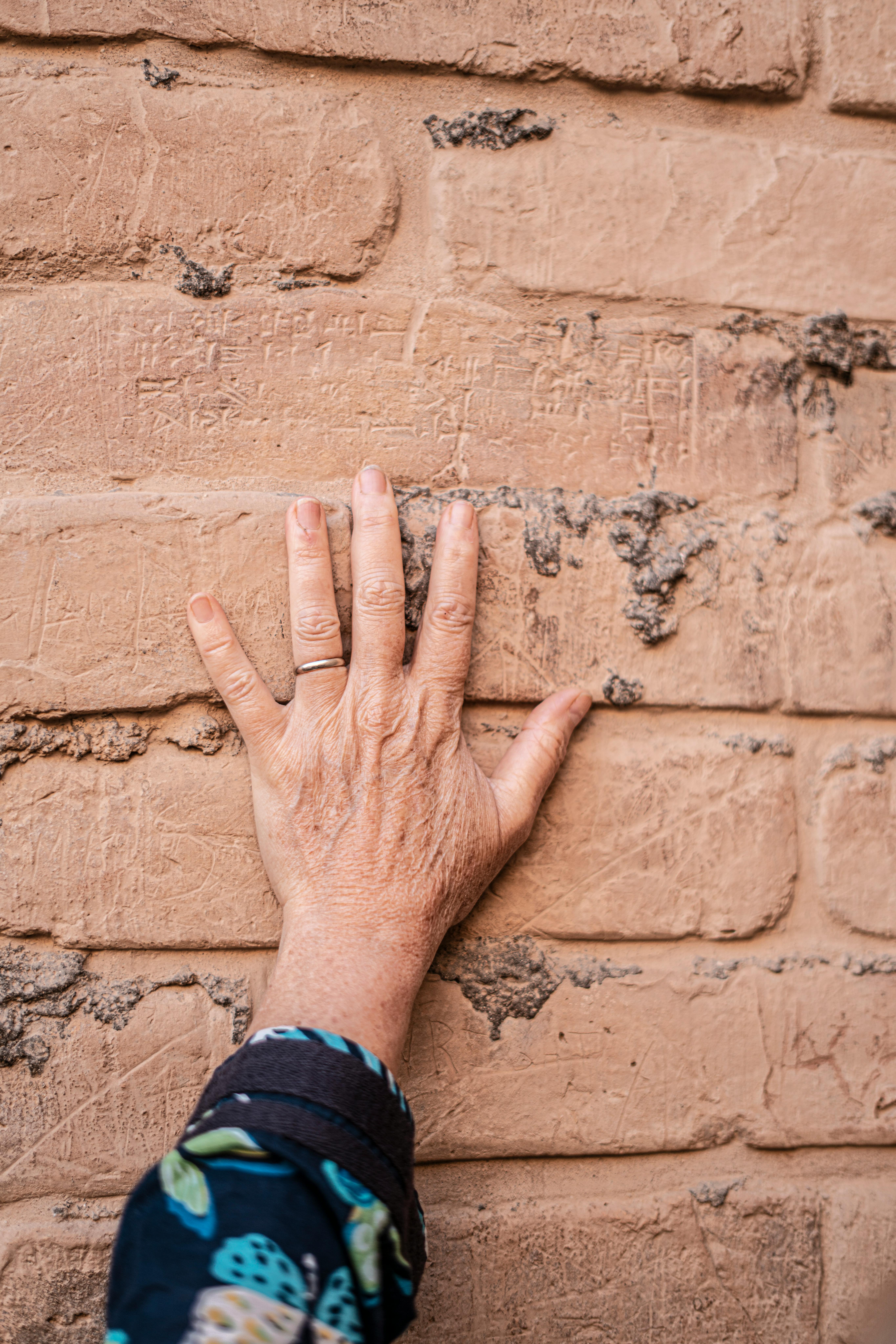 Close-up of Womans Hand Touching an Ancient Brick Wall · Free Stock Photo