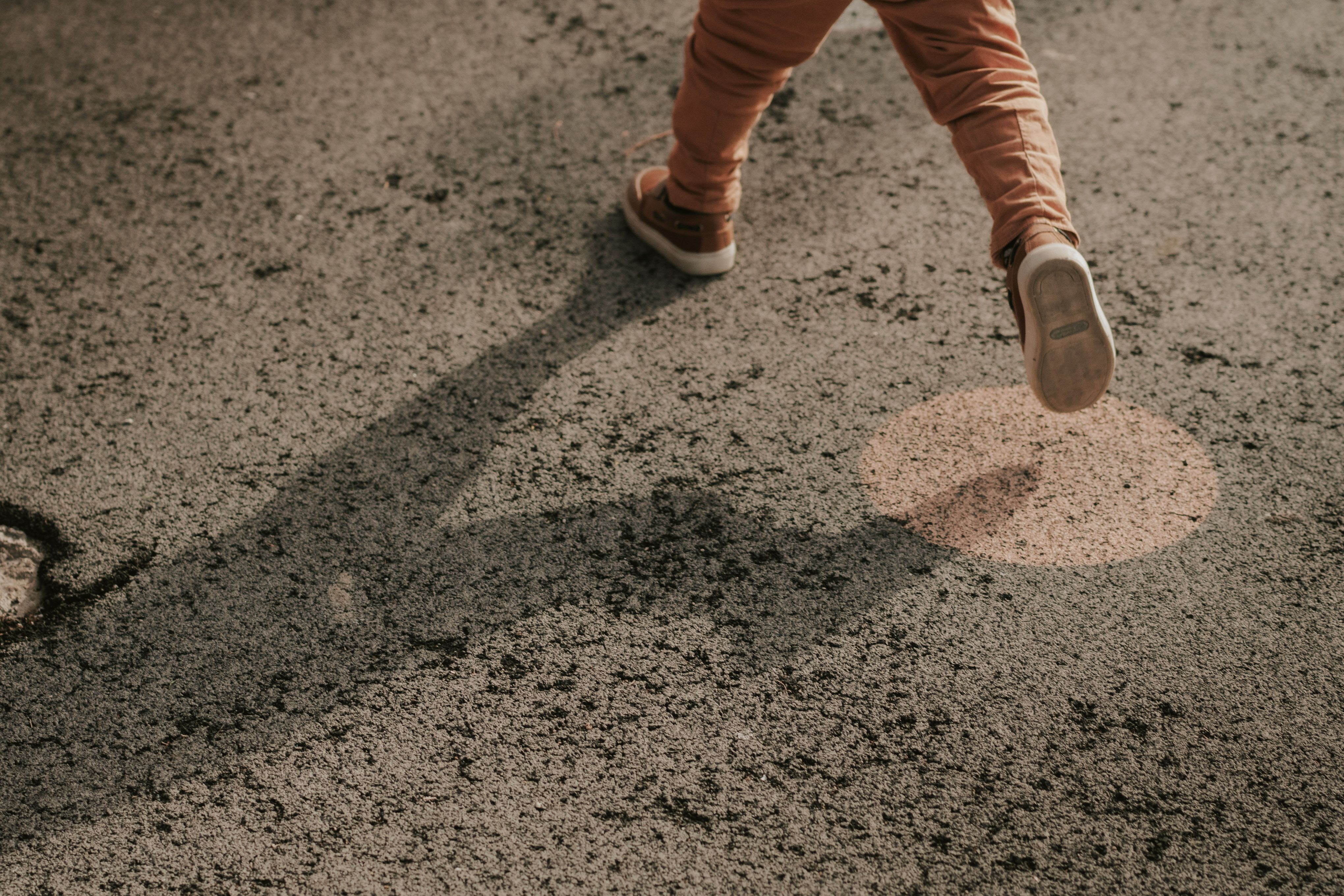 Legs of a Child Playing a Game on a Sidewalk · Free Stock Photo
