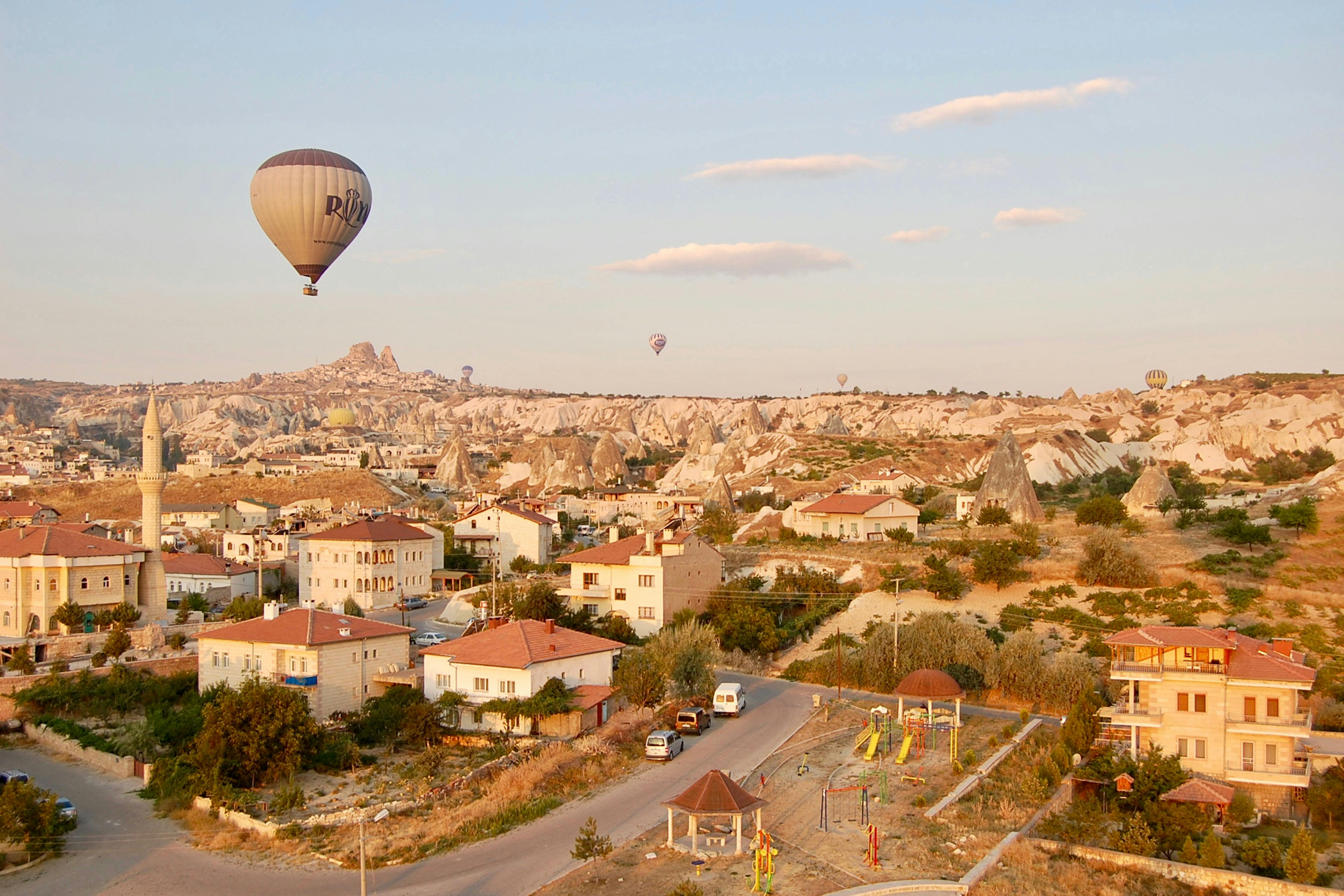 Hot Air Balloon Flying over Town in Cappadocia · Free Stock Photo