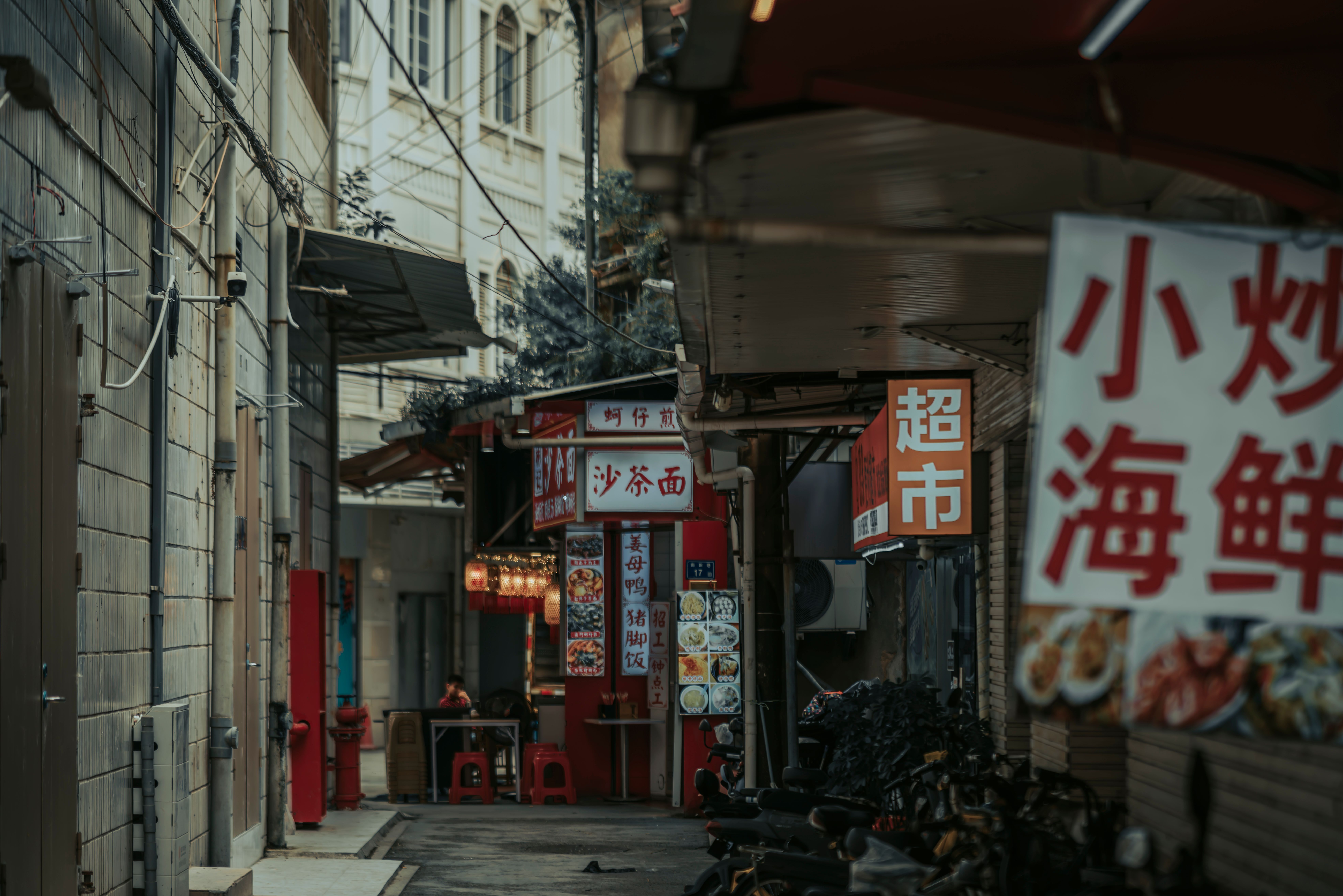 A narrow alley with chinese signs and people walking · Free Stock Photo