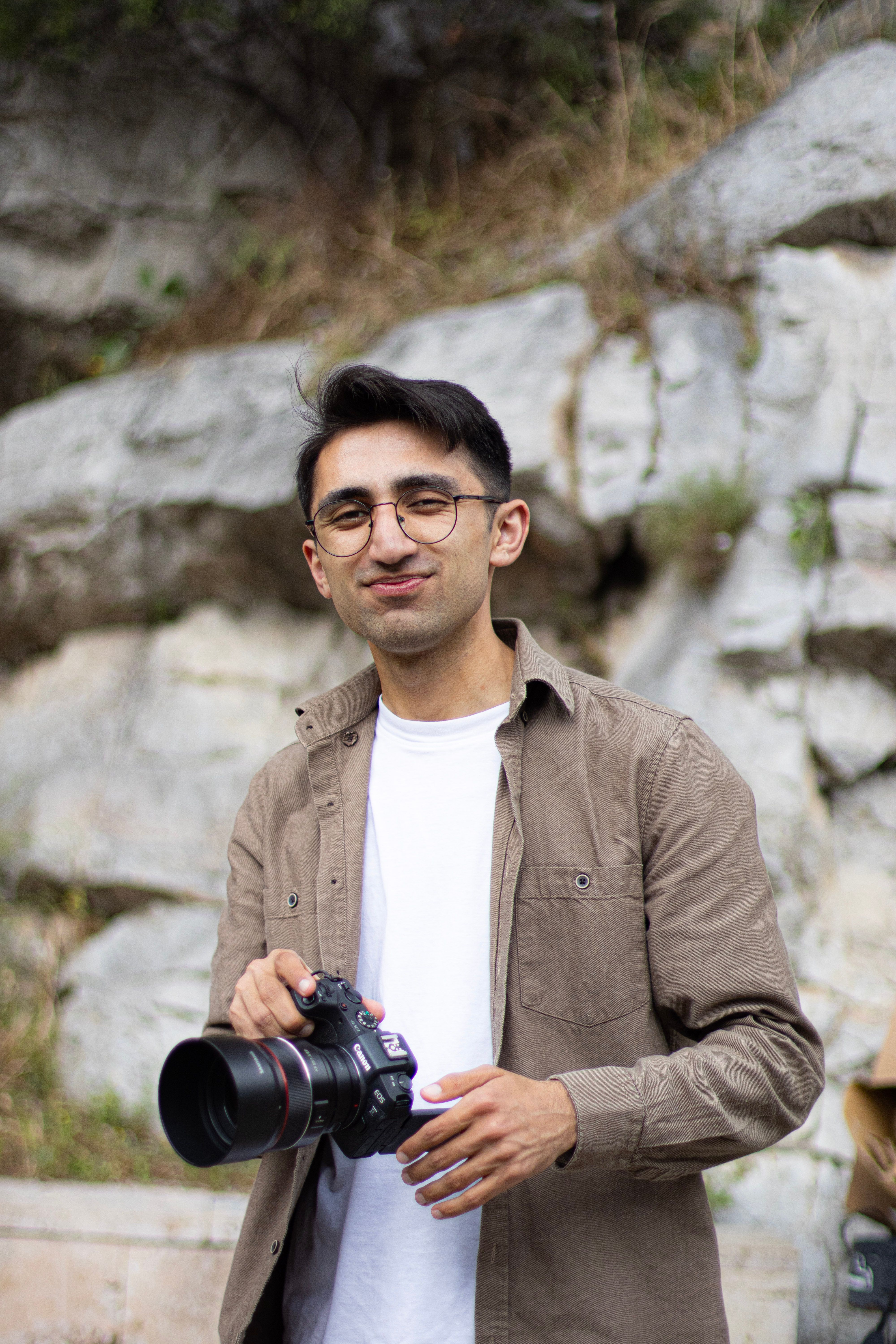 Man in Black Suit Holding Canon Dslr Camera · Free Stock Photo