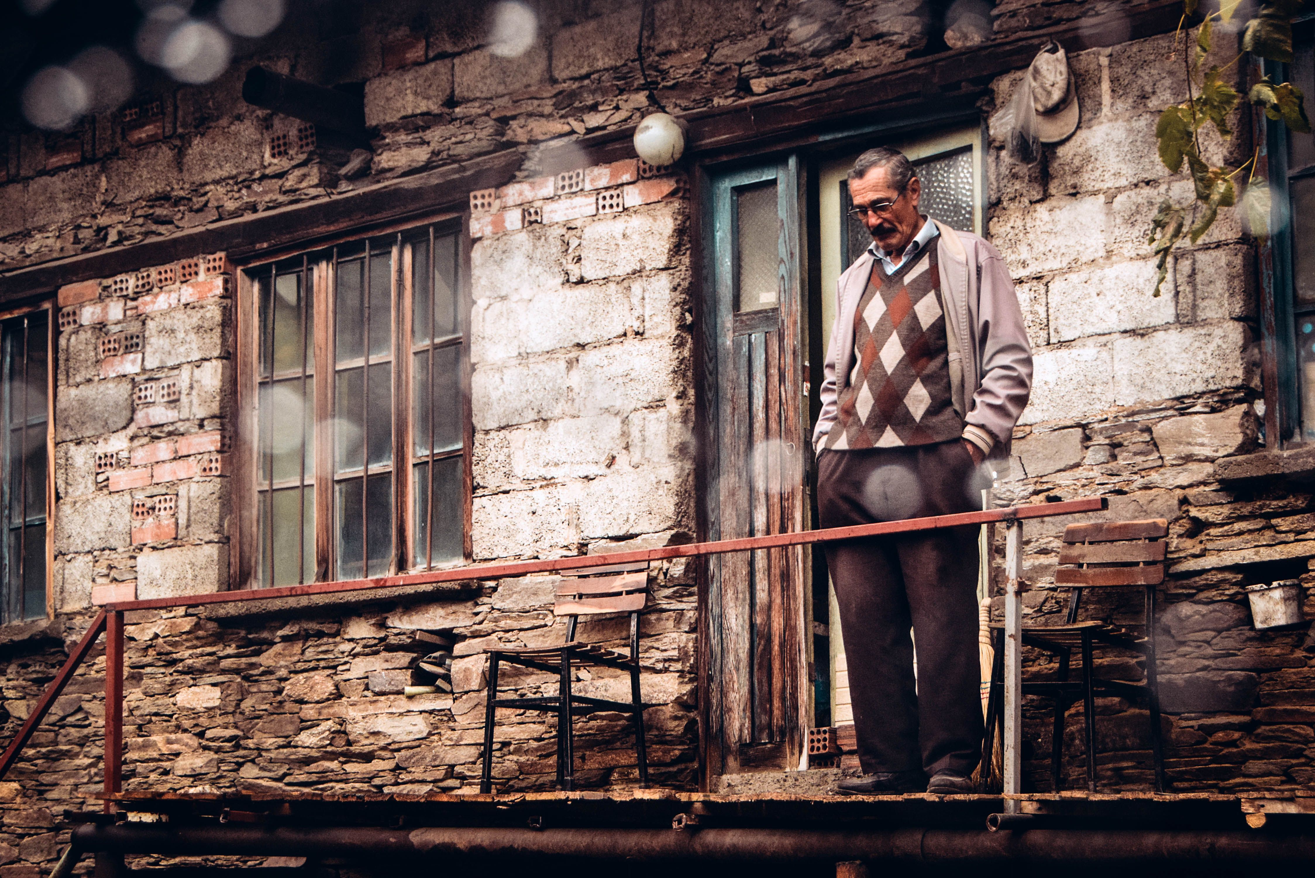 Man Standing on Brown House Balcony · Free Stock Photo