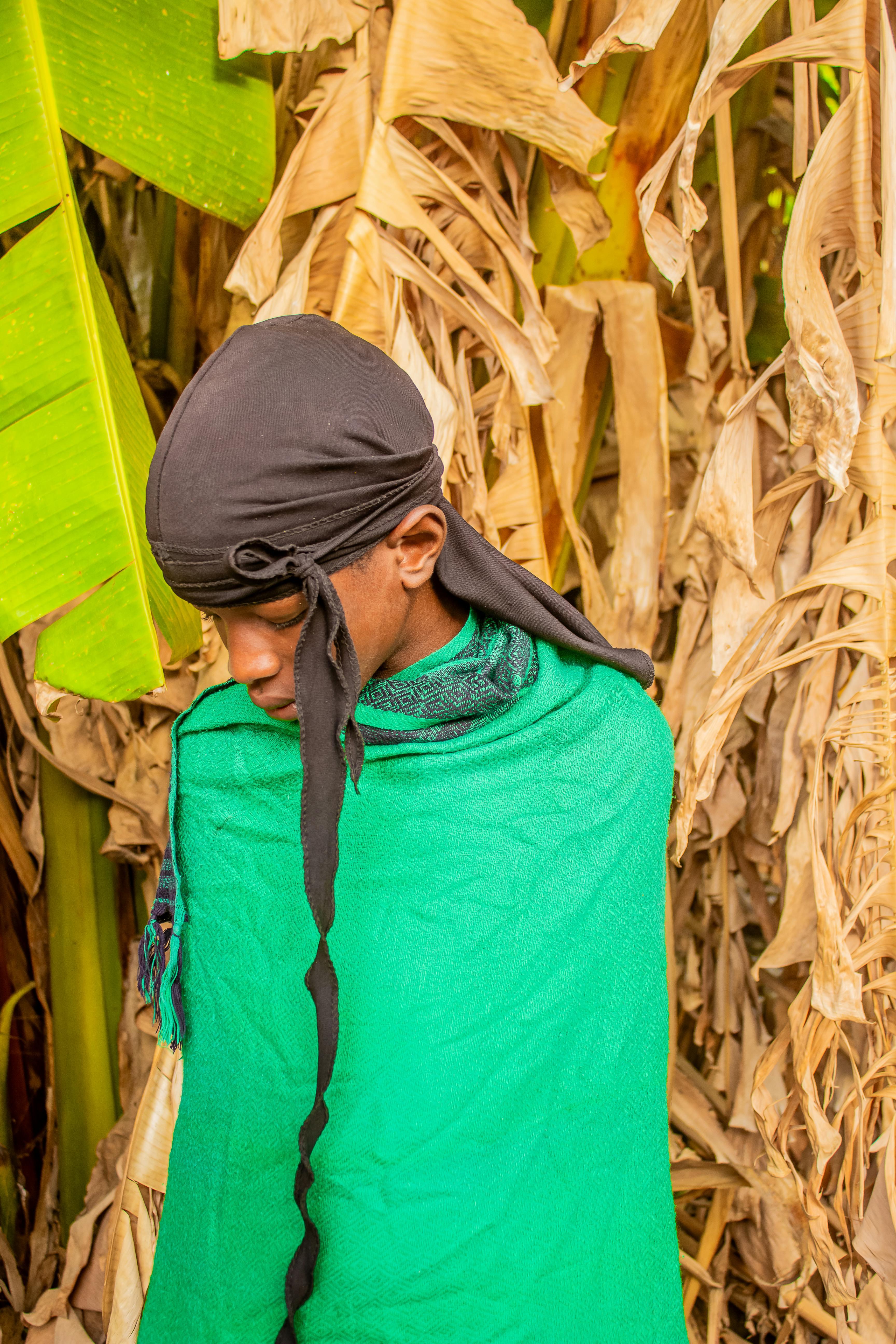 A young man in a green scarf standing in front of a corn field · Free ...