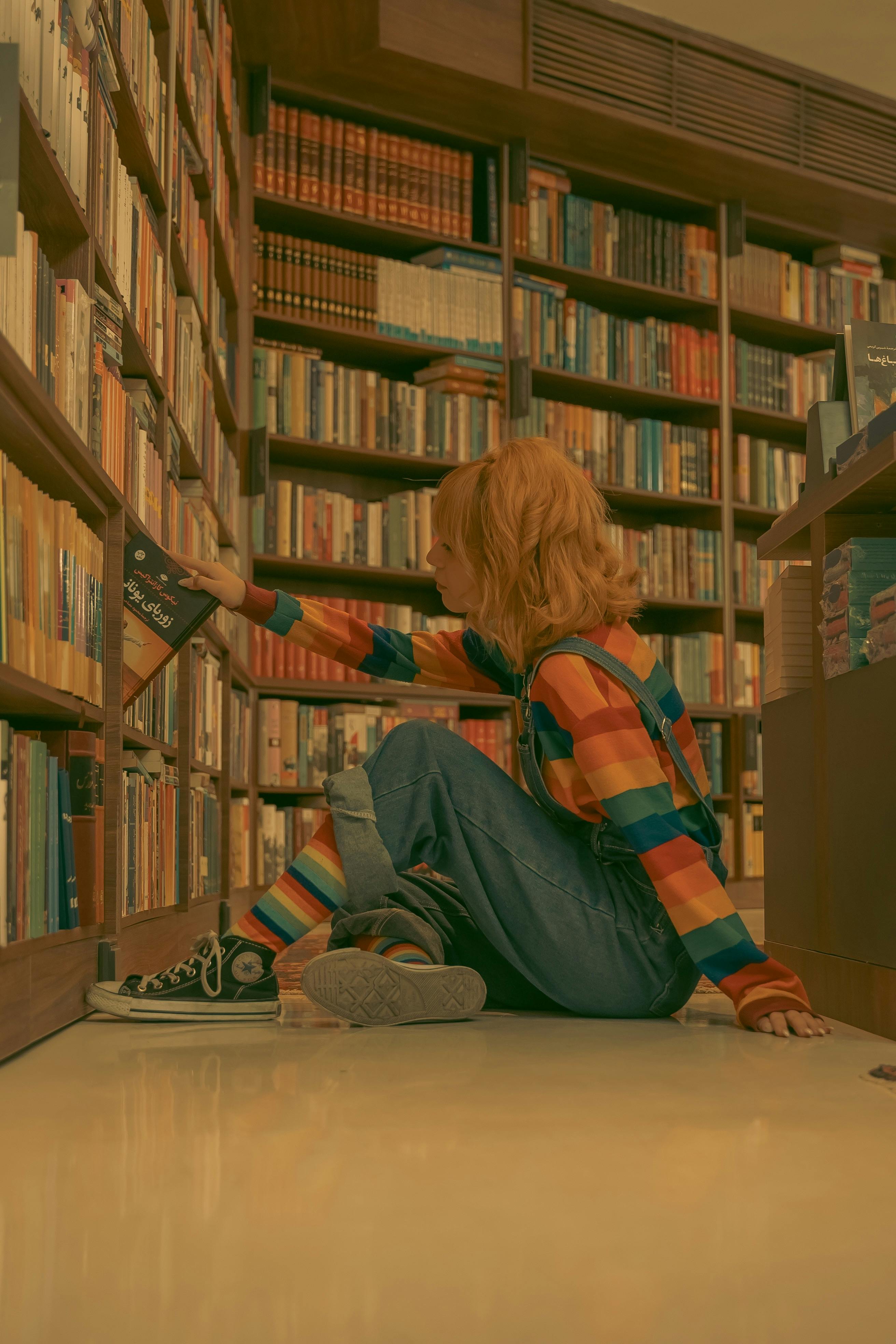 Young Woman Picking Up a Book in a Library · Free Stock Photo