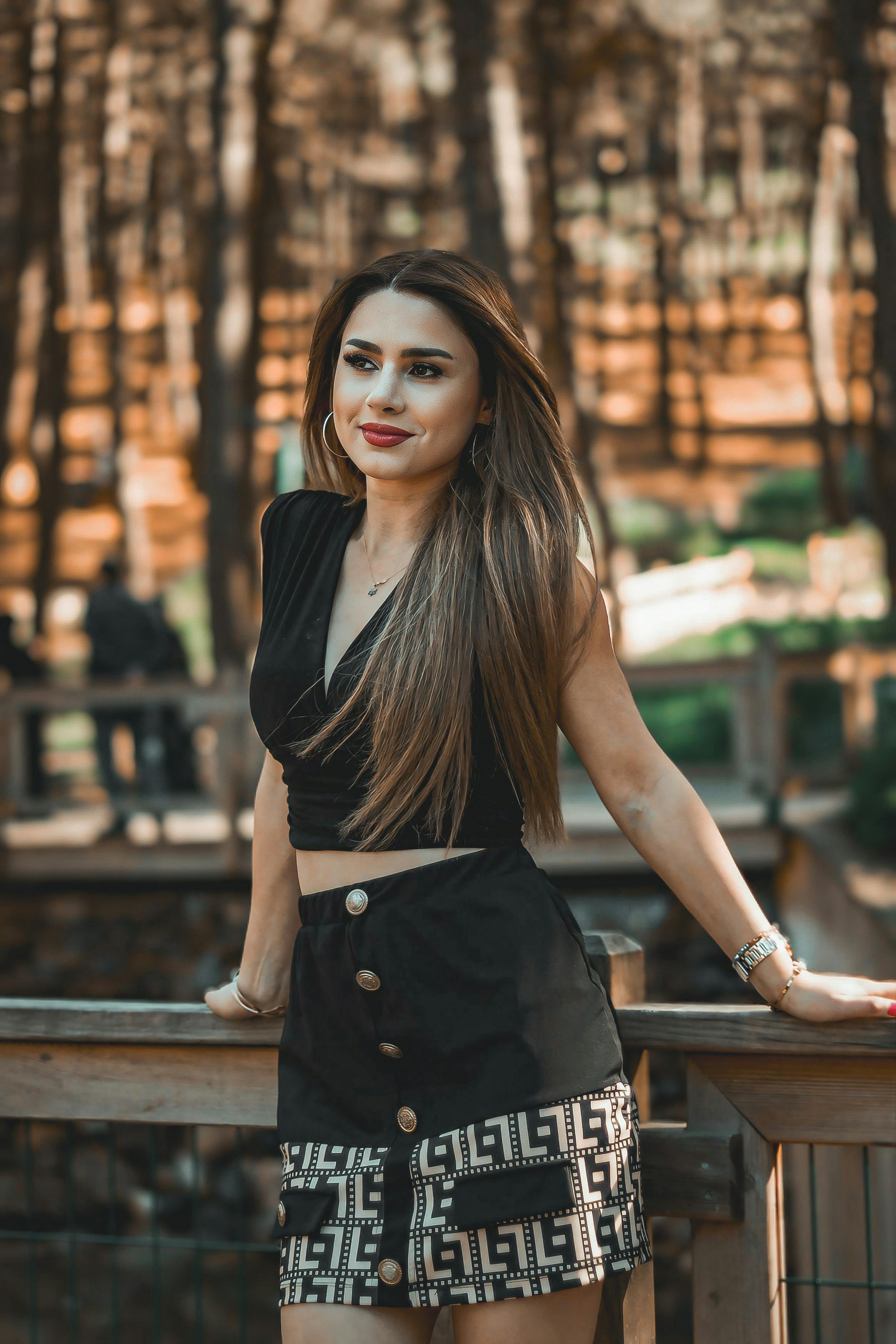 Brunette Woman Wearing Black Crop Top and Patter Skirt Leaning against ...