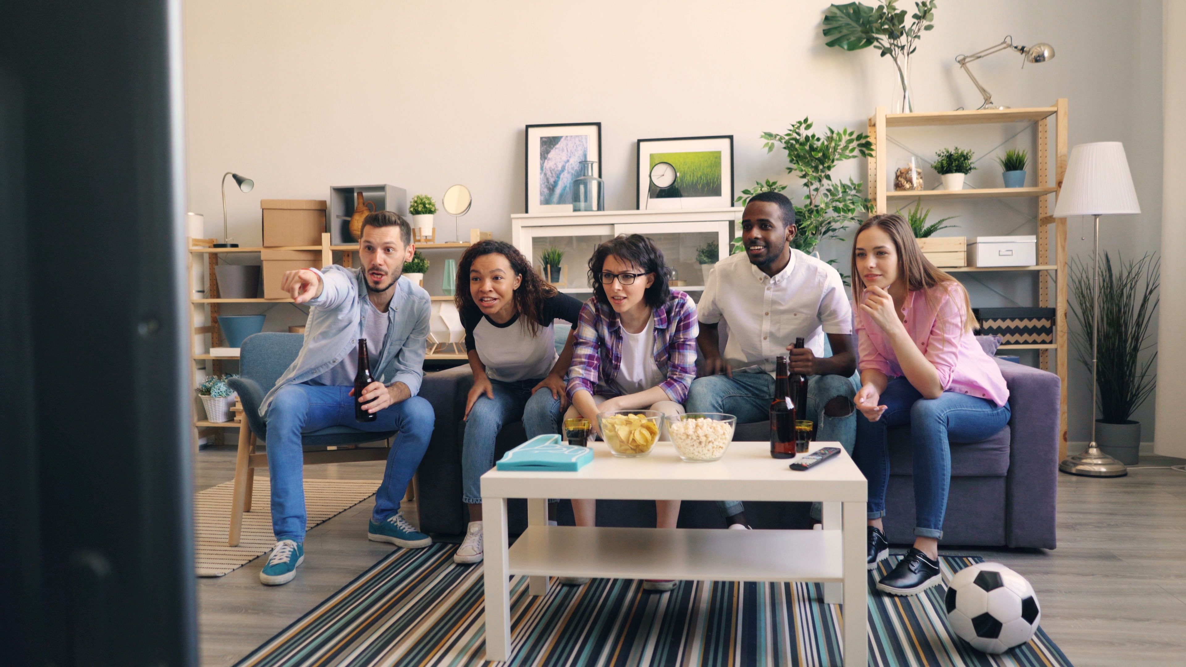 A group of people sitting on a couch watching tv · Free Stock Photo
