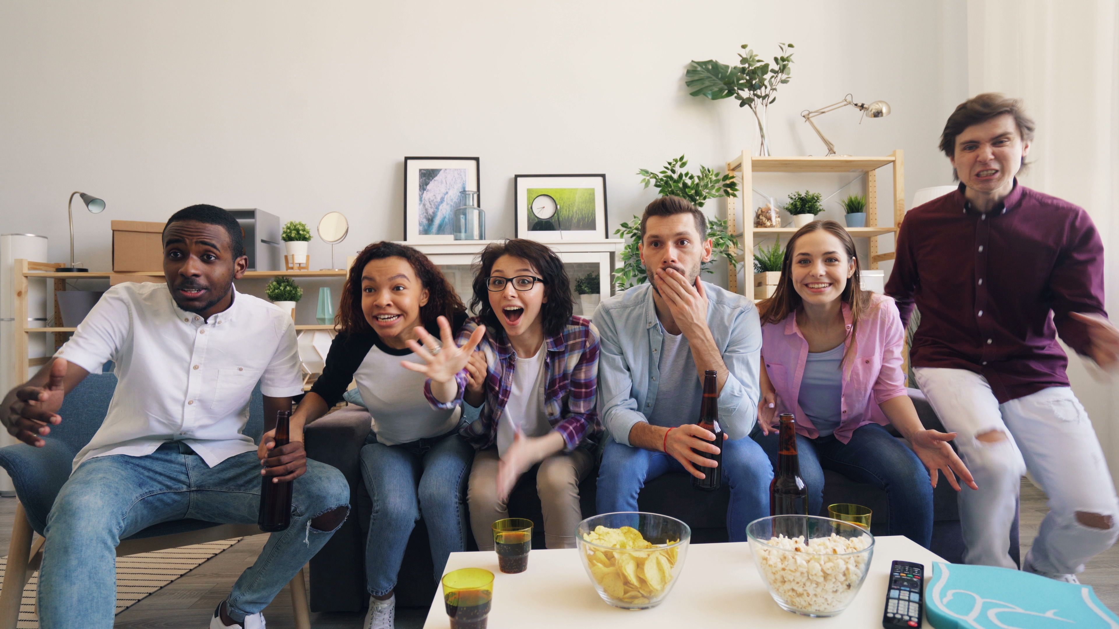 Group of young people sitting on couch and watching tv · Free Stock Photo