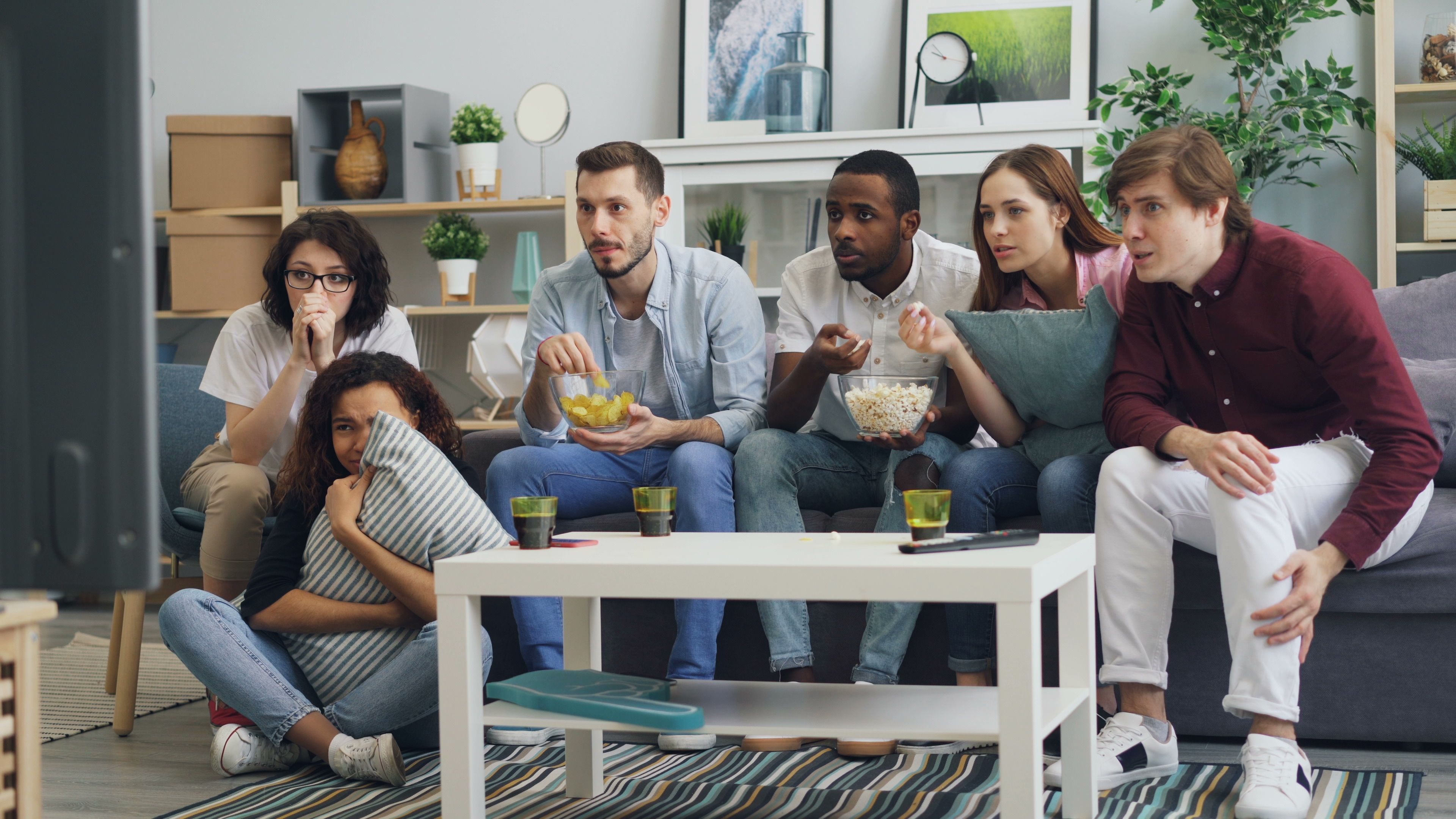 A group of people sitting on a couch watching tv · Free Stock Photo