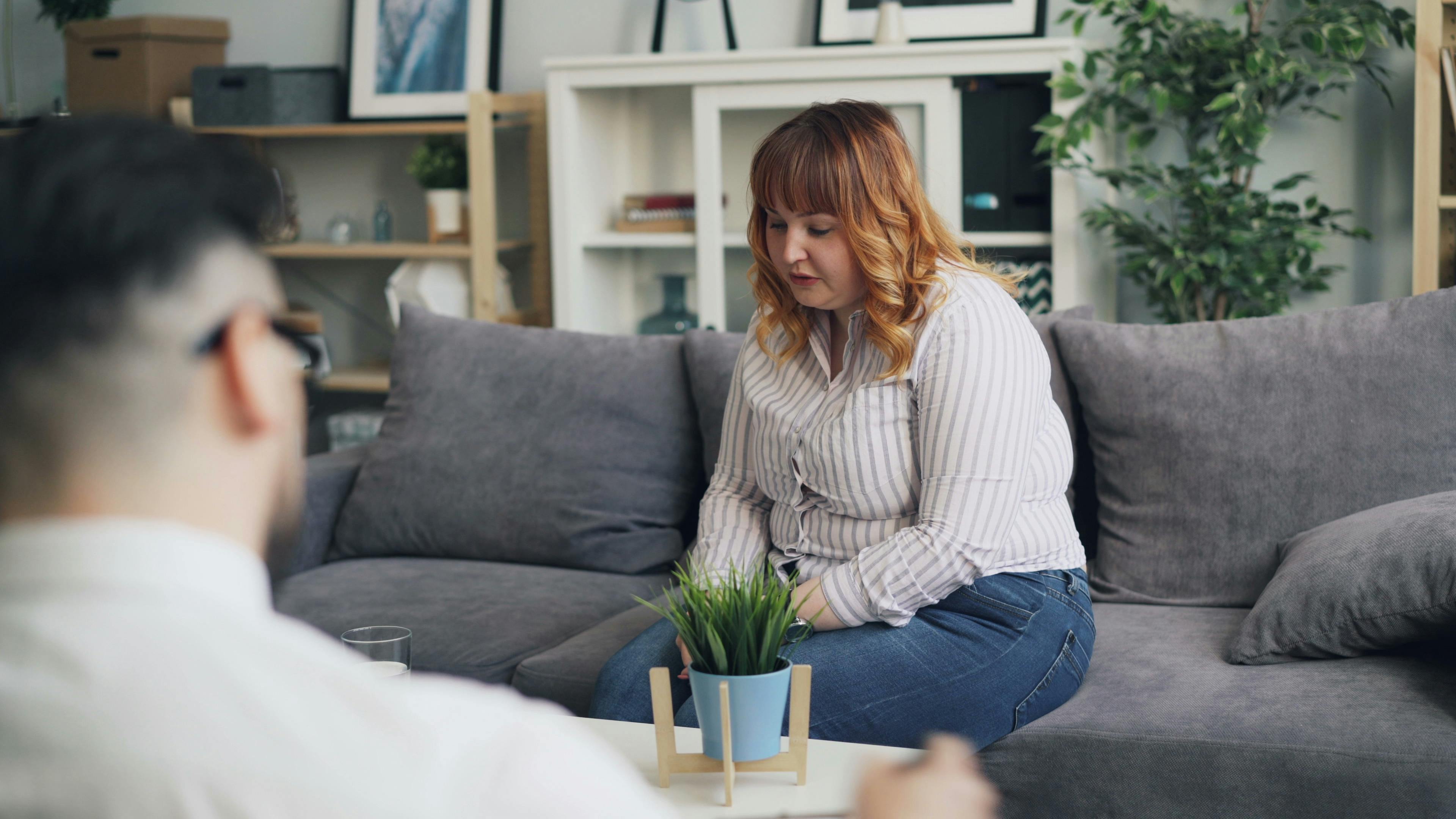 A woman sitting on a couch talking to a man · Free Stock Photo