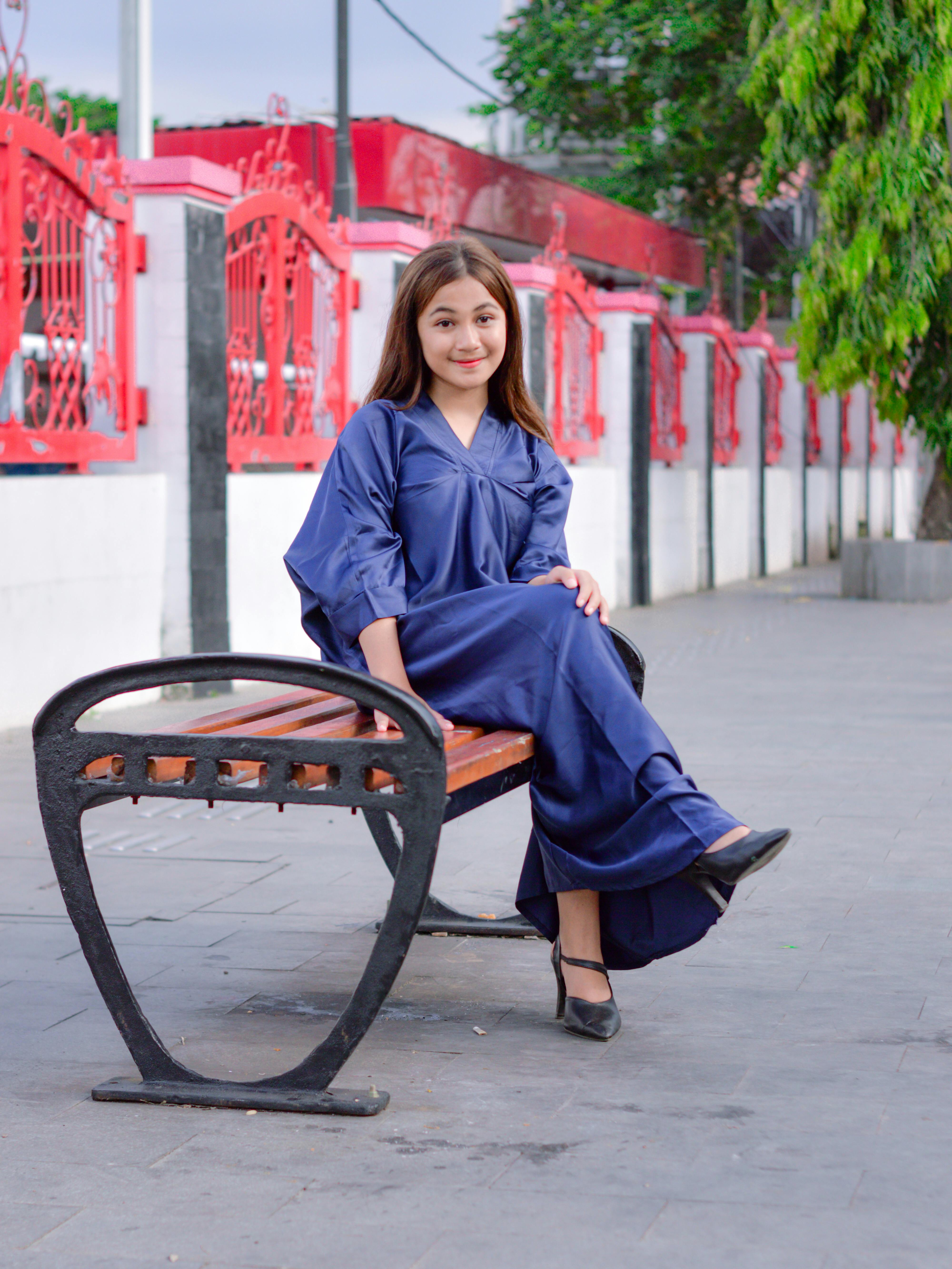Woman in Blue Graduation Gown Sitting on Bench · Free Stock Photo