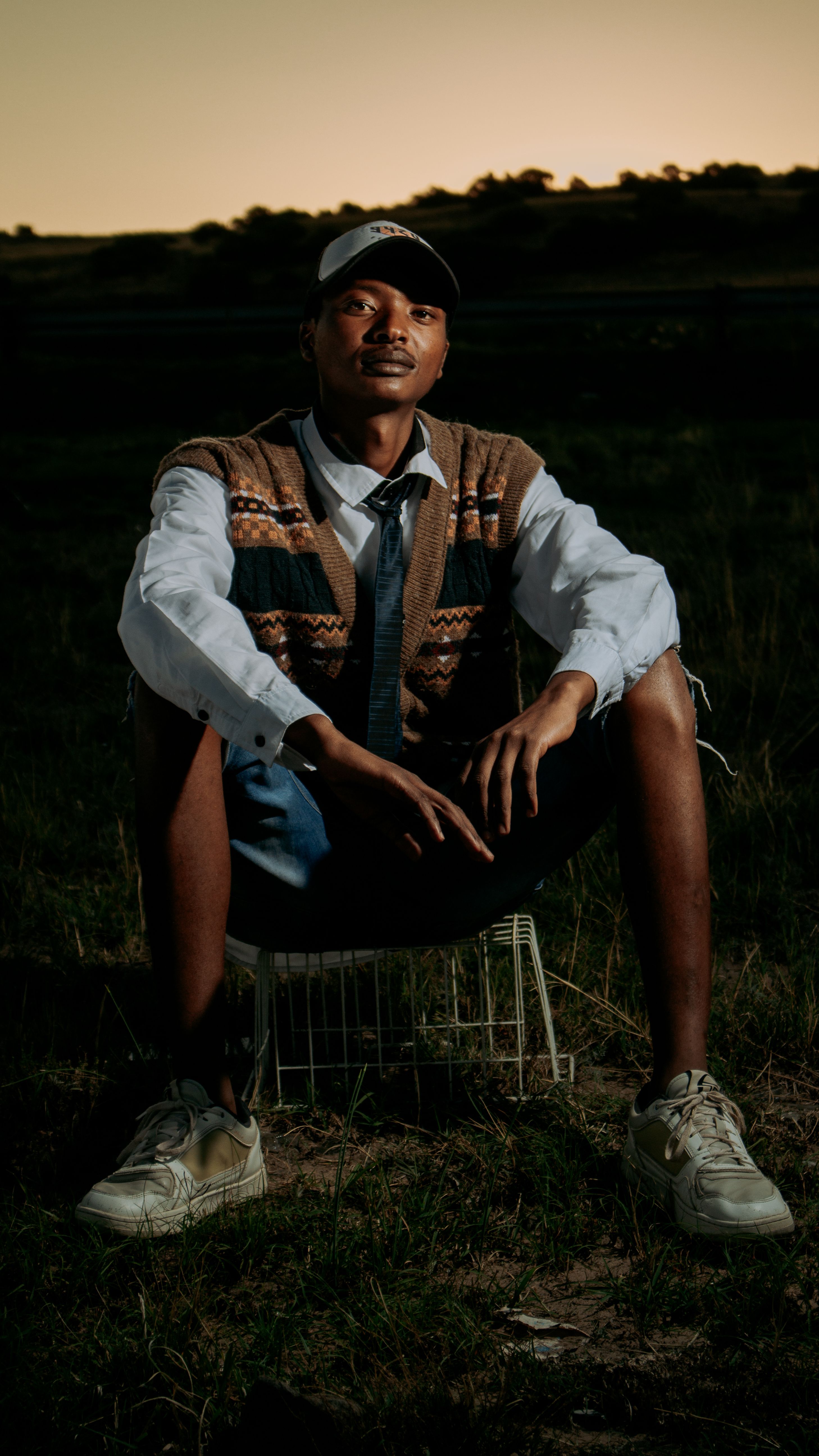 Man in Cap Sitting in Jacket at Dusk · Free Stock Photo