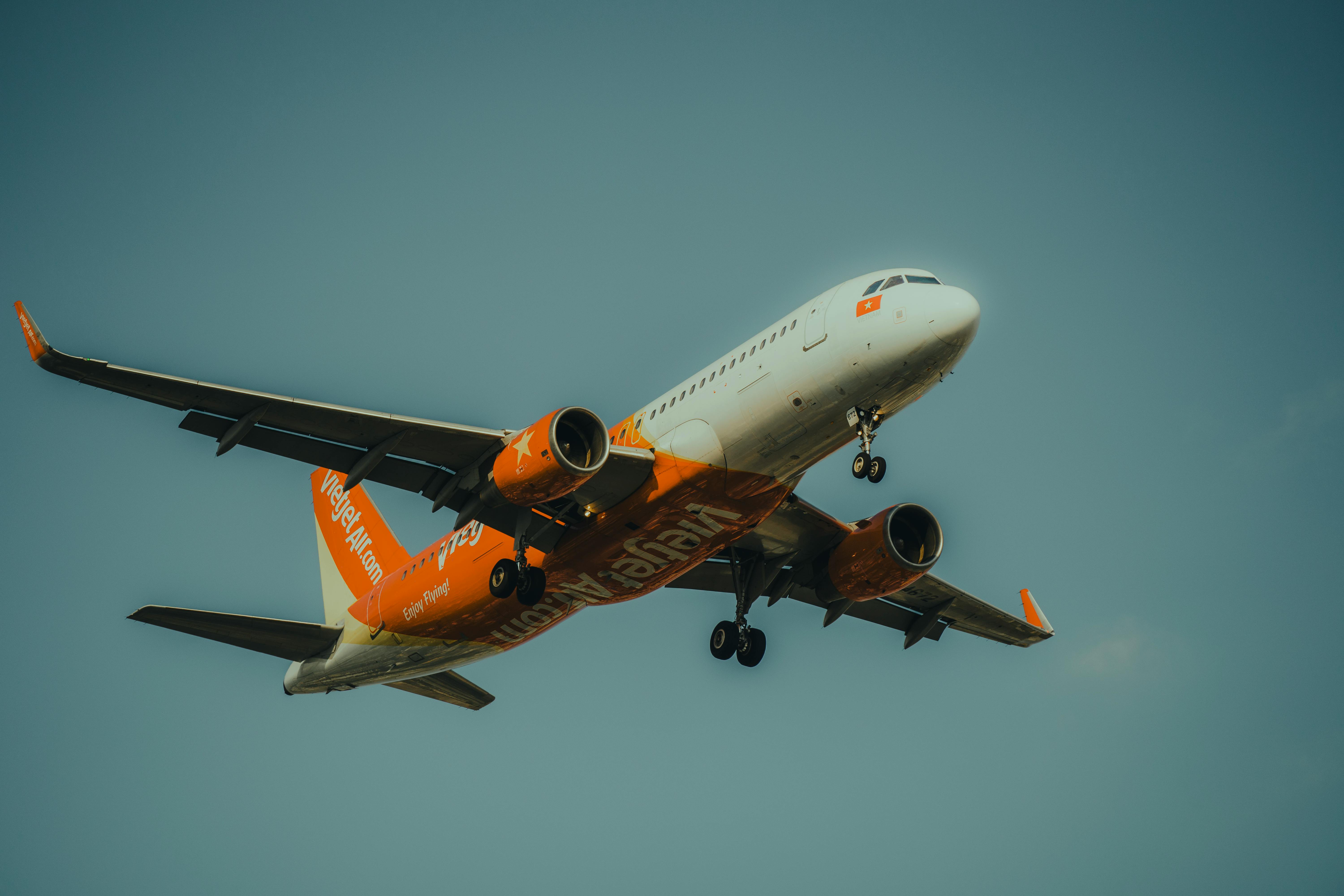 An orange and white airplane flying in the sky · Free Stock Photo