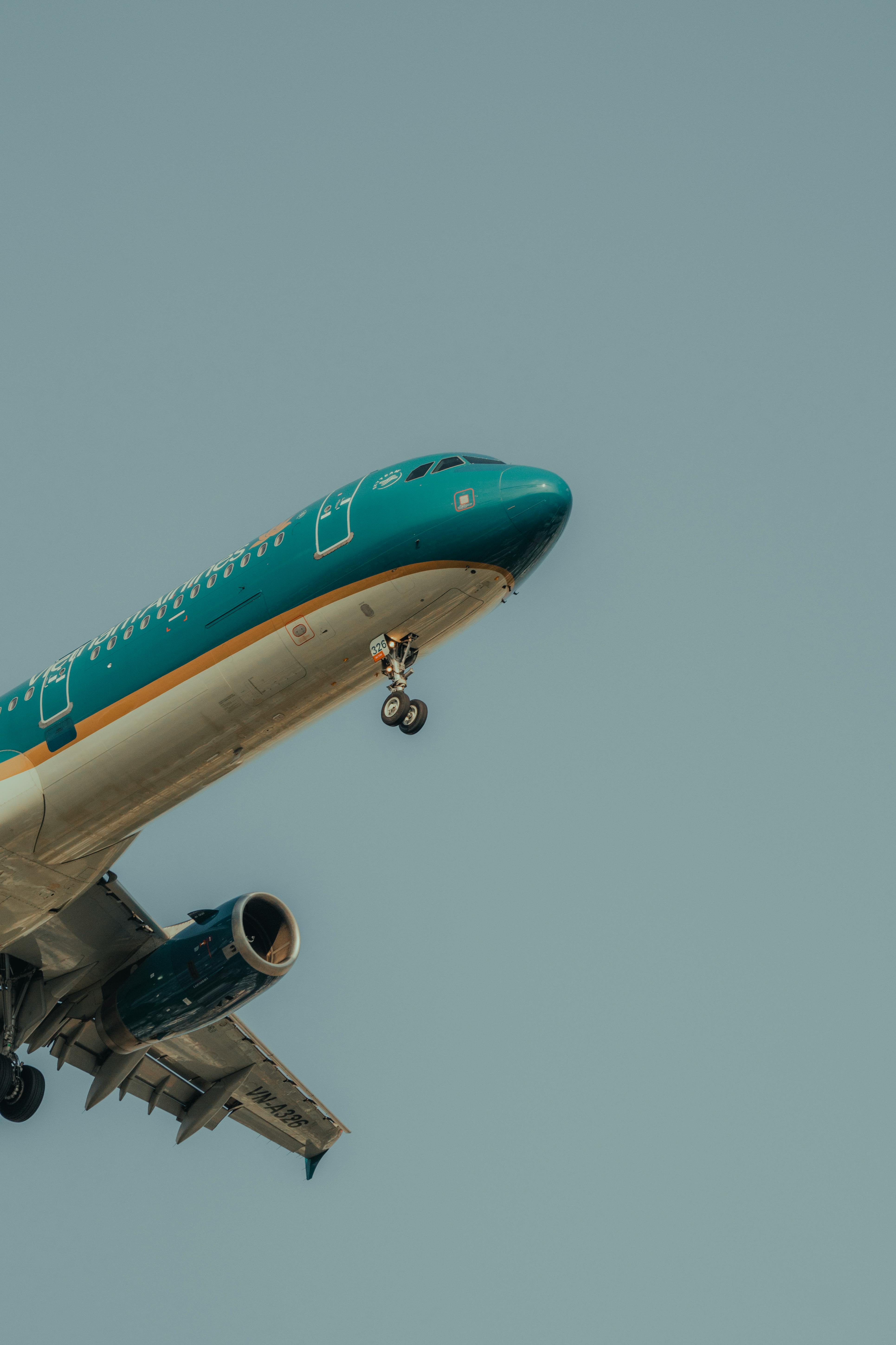 A large blue and teal airplane flying in the sky · Free Stock Photo