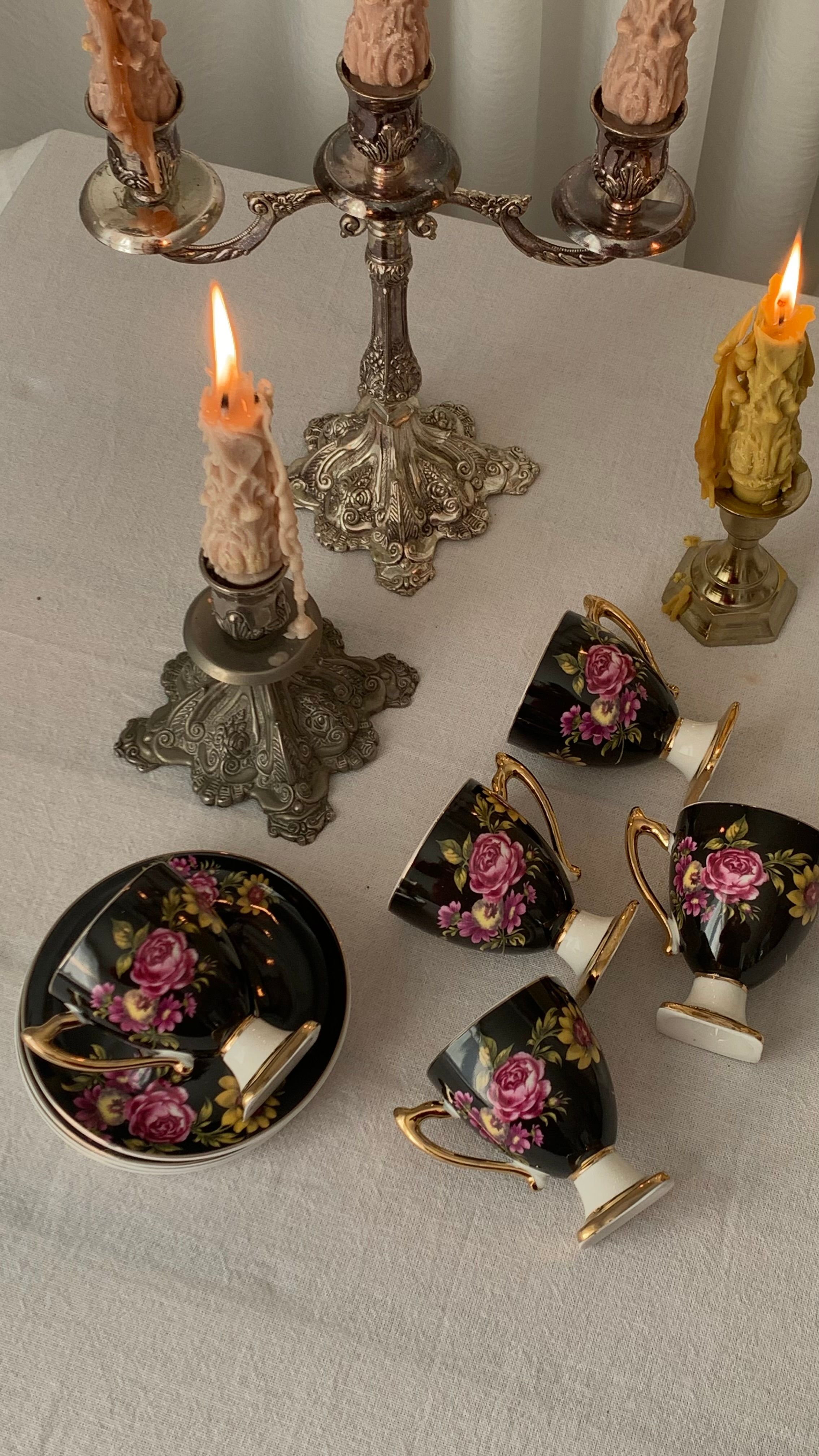 A Collection of Cups with Floral Patterns Lying on a Table with Candles ...