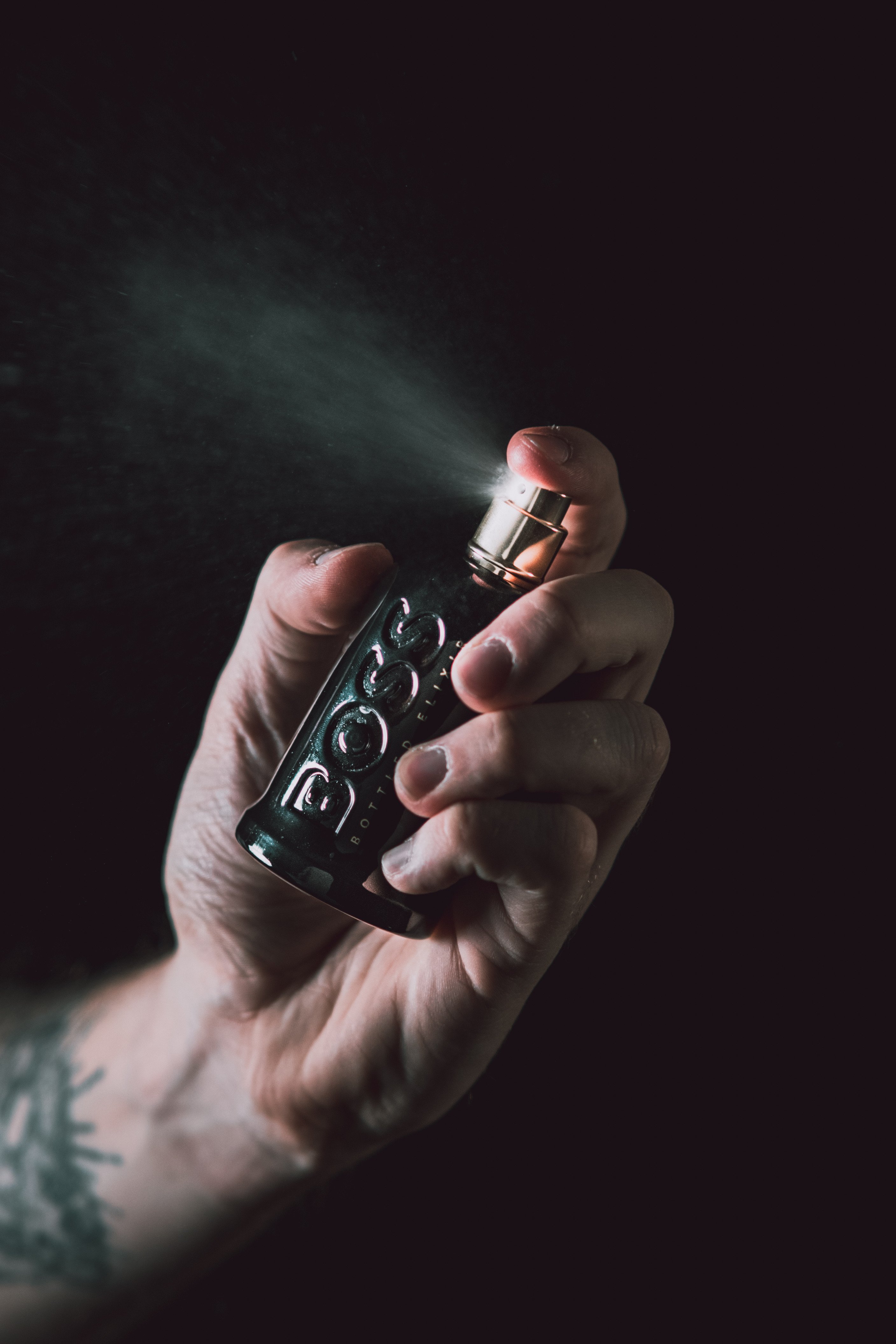 Man Hand Holding Perfume and Spraying it · Free Stock Photo
