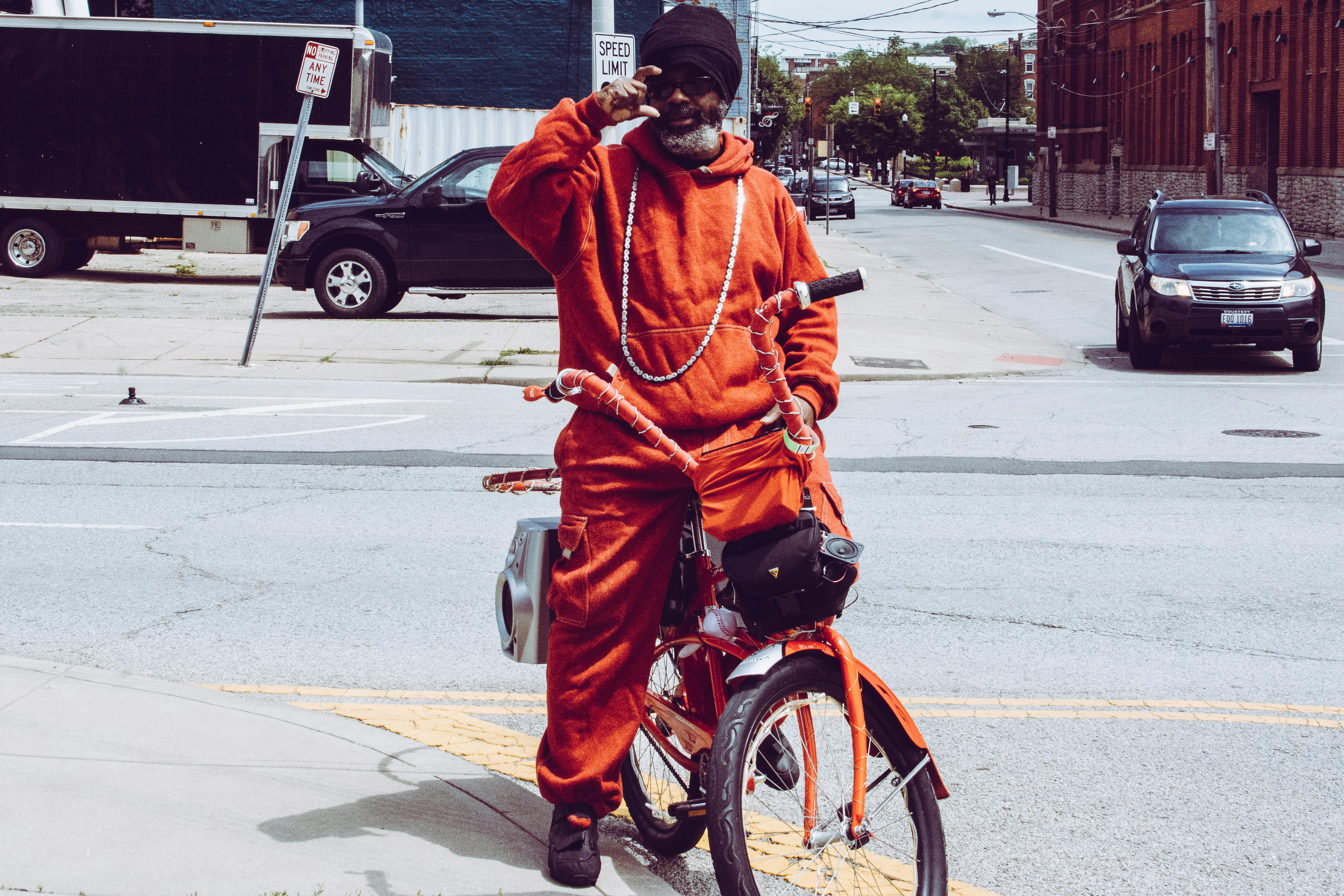 Man Wearing Orange Jacket Riding On Bike · Free Stock Photo