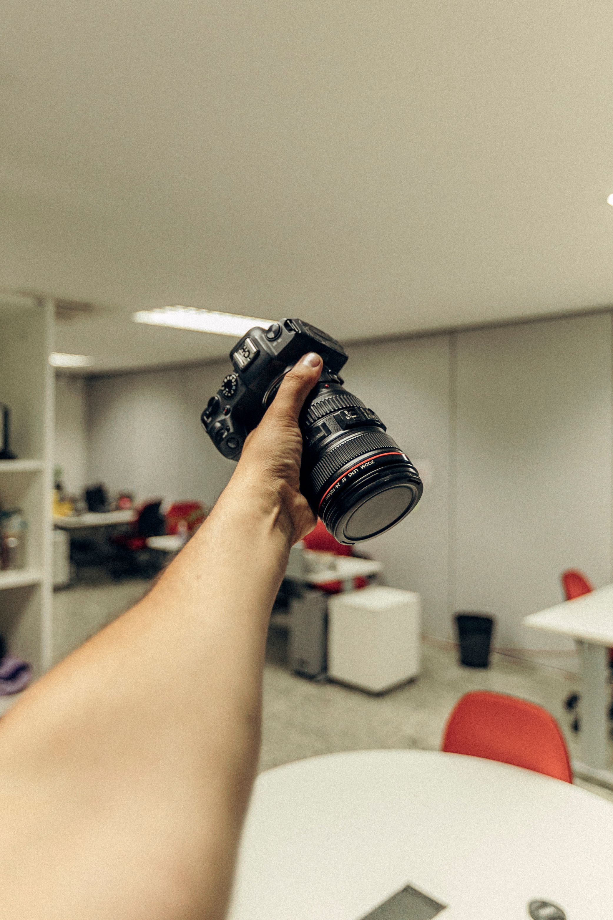 Holding the Camera by the Lens in the Office · Free Stock Photo