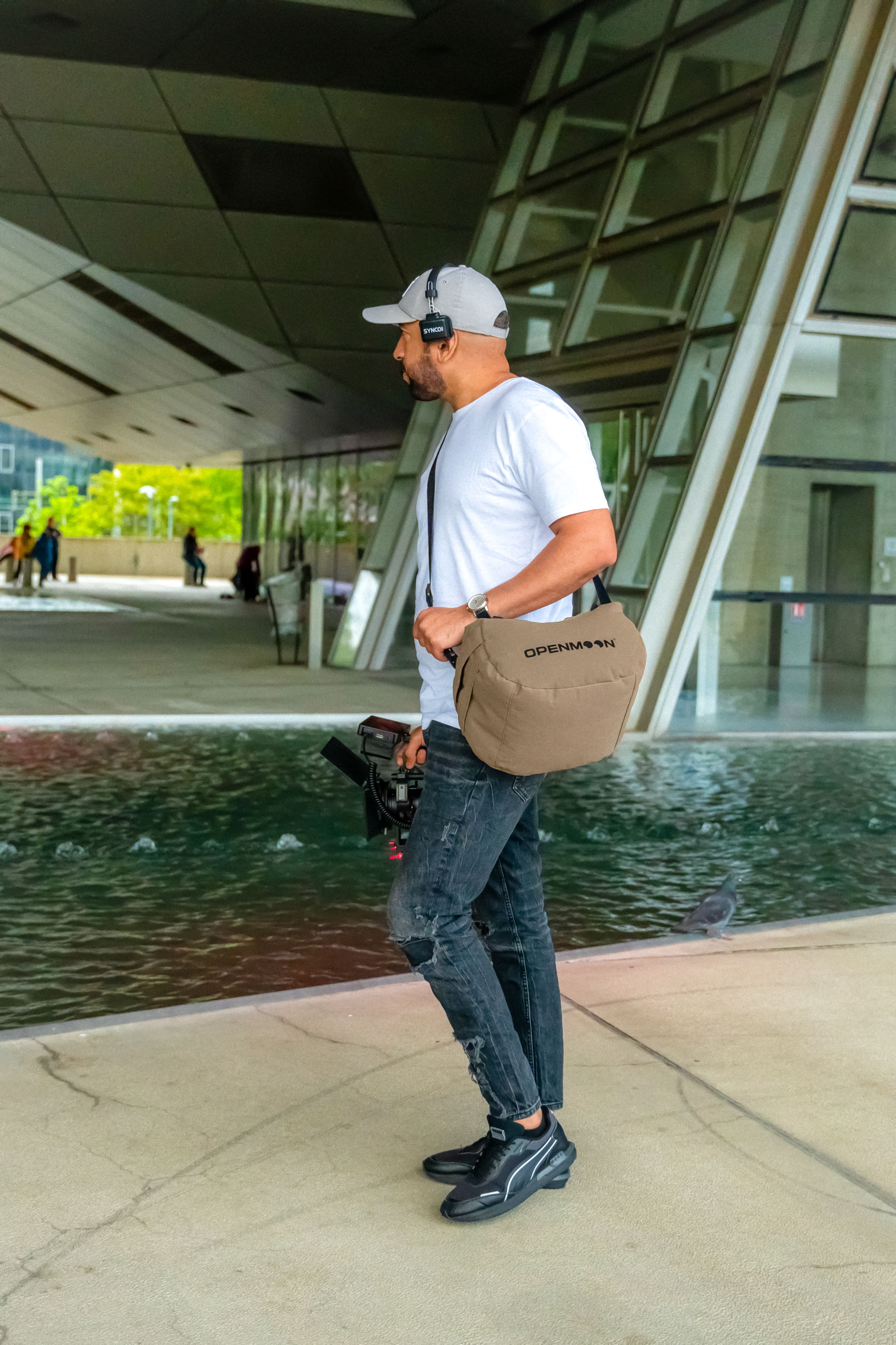 A man walking with a camera and a bag · Free Stock Photo