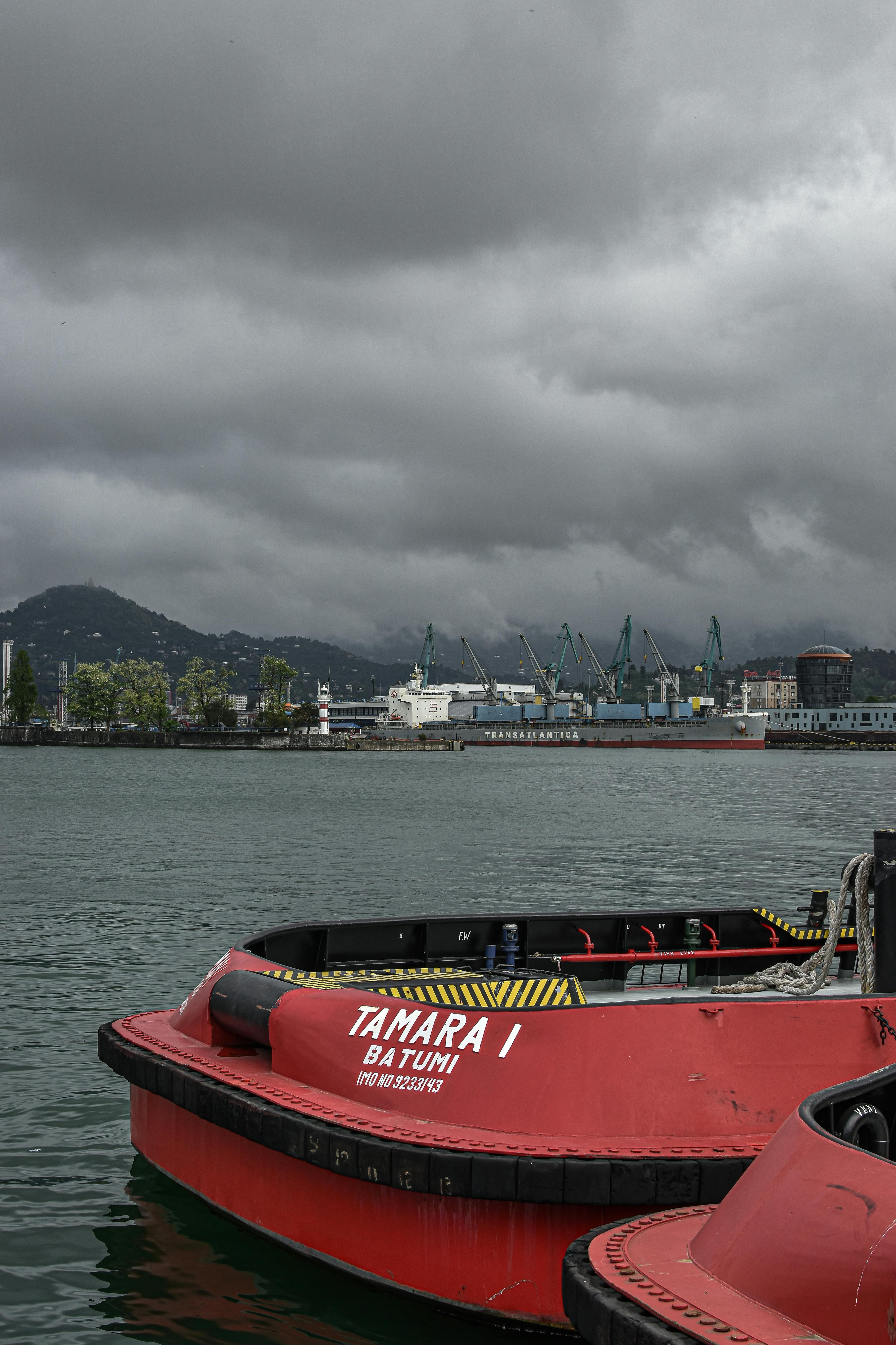 Small Red Boats Sailing next to Industrial Port during Storm · Free ...