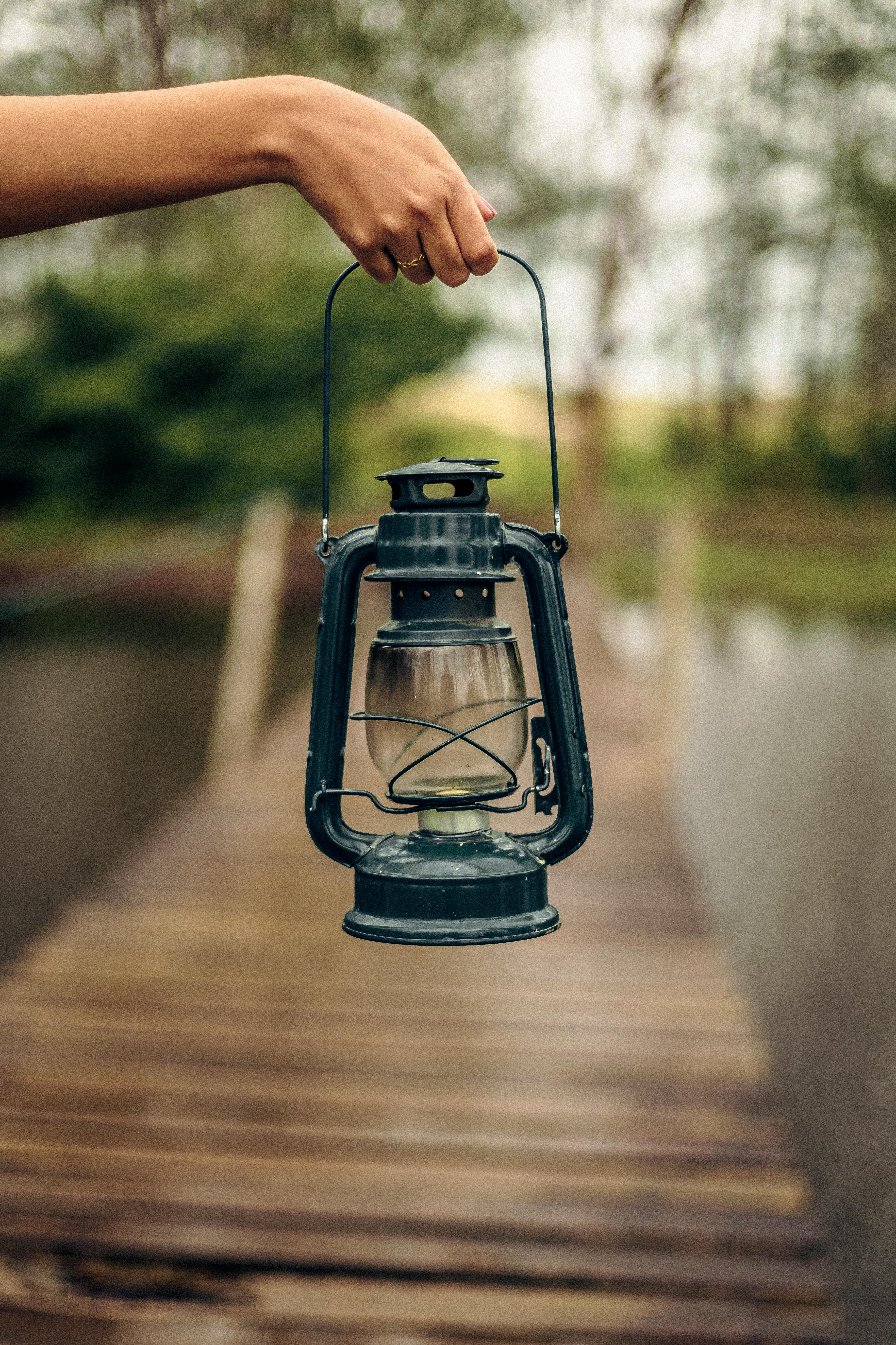 Person Hand Holding Lantern over Boardwalk · Free Stock Photo