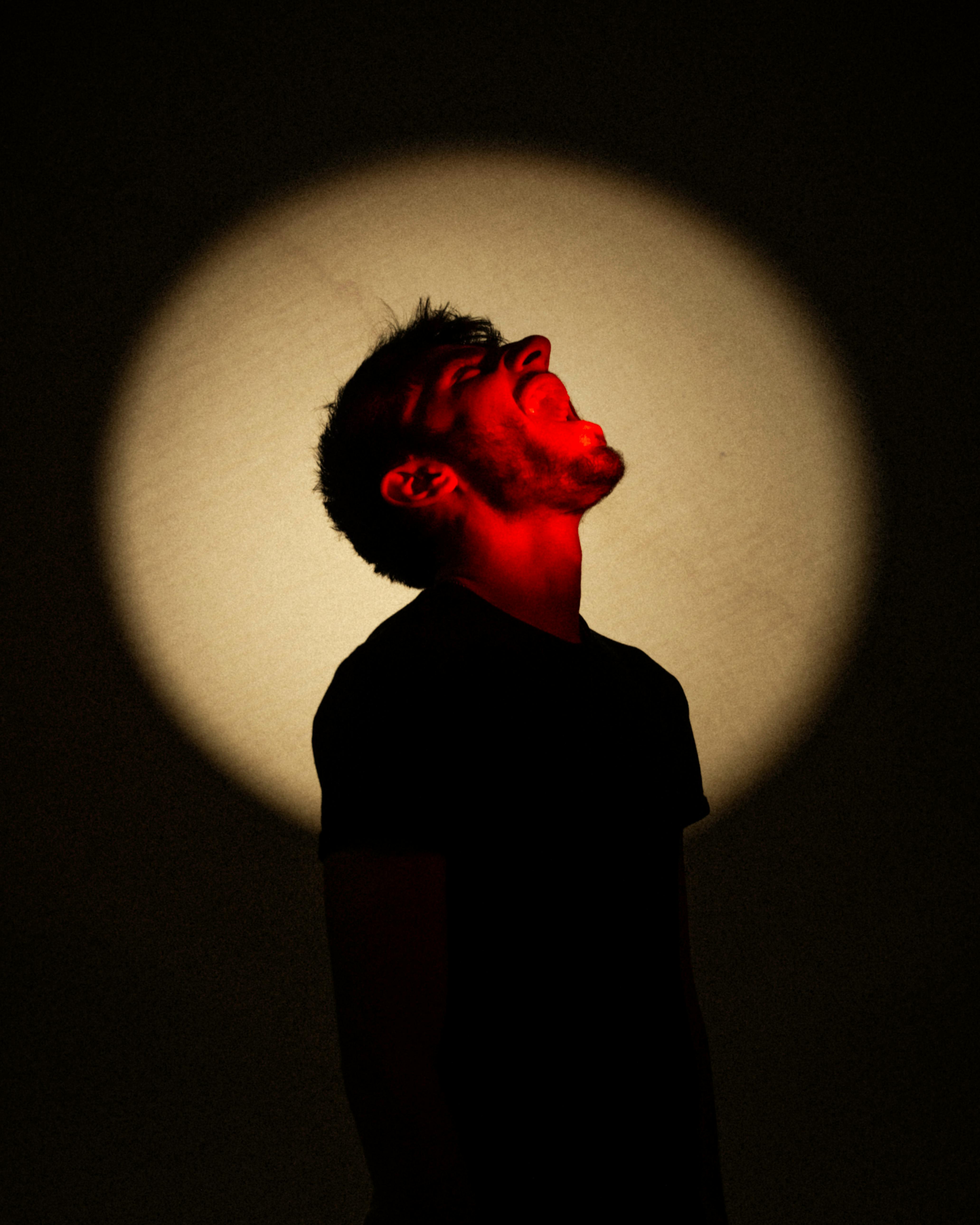 Photo of a Young Man with His Face Illuminated by Red and Yellow Light ...