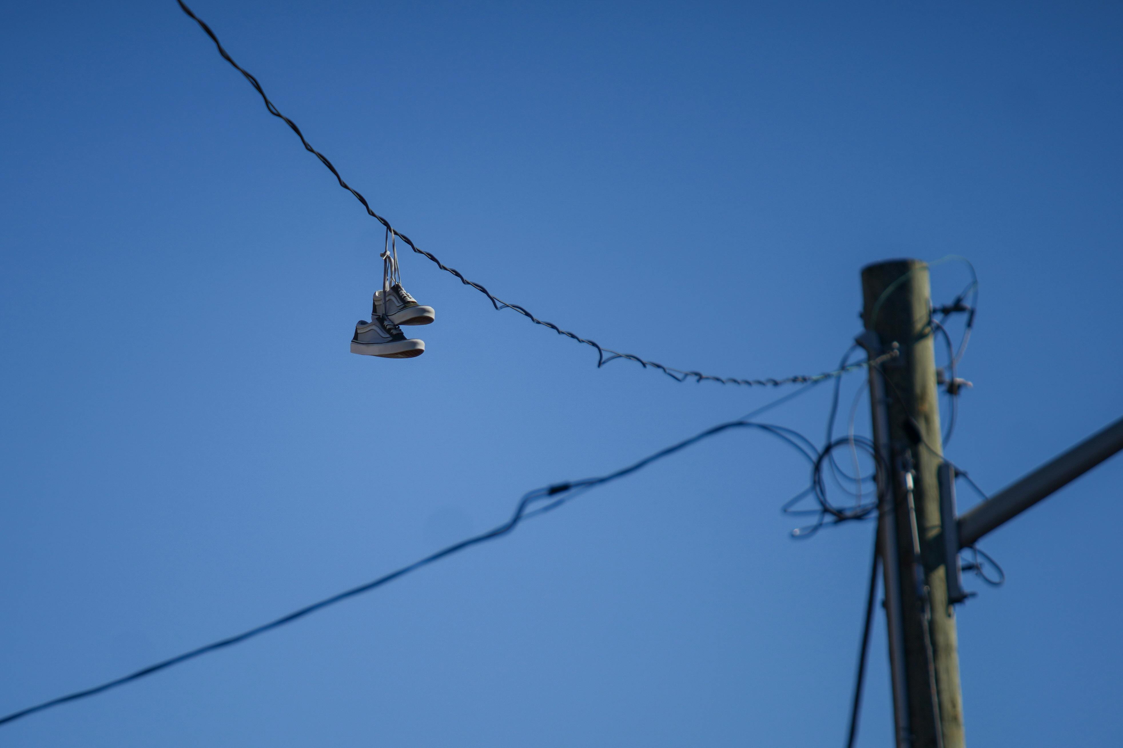 Power Line Wire with Shoes Hanging on Shoelaces · Free Stock Photo