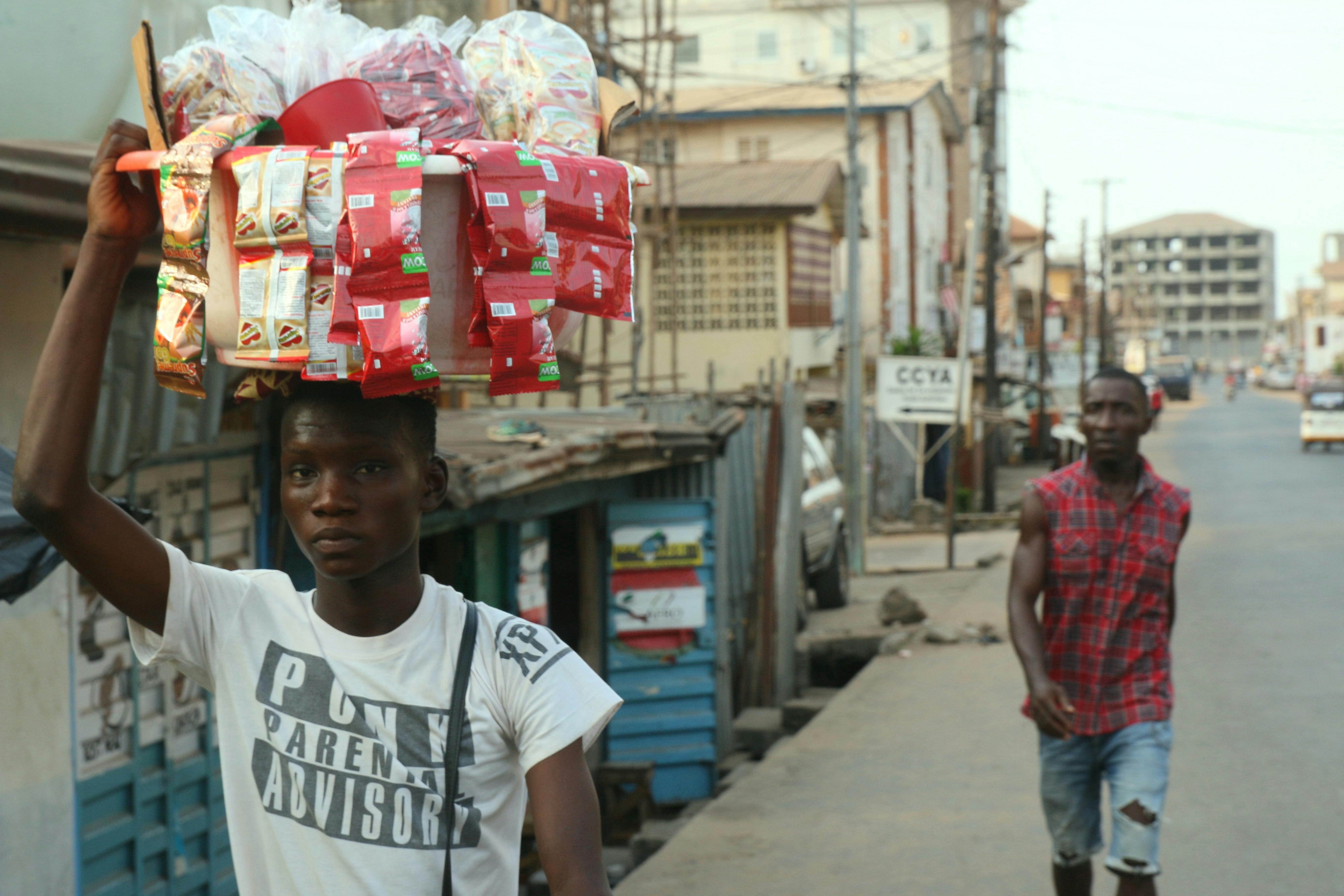 Men Walking on Street in Town and Carrying Bags on Head · Free Stock Photo