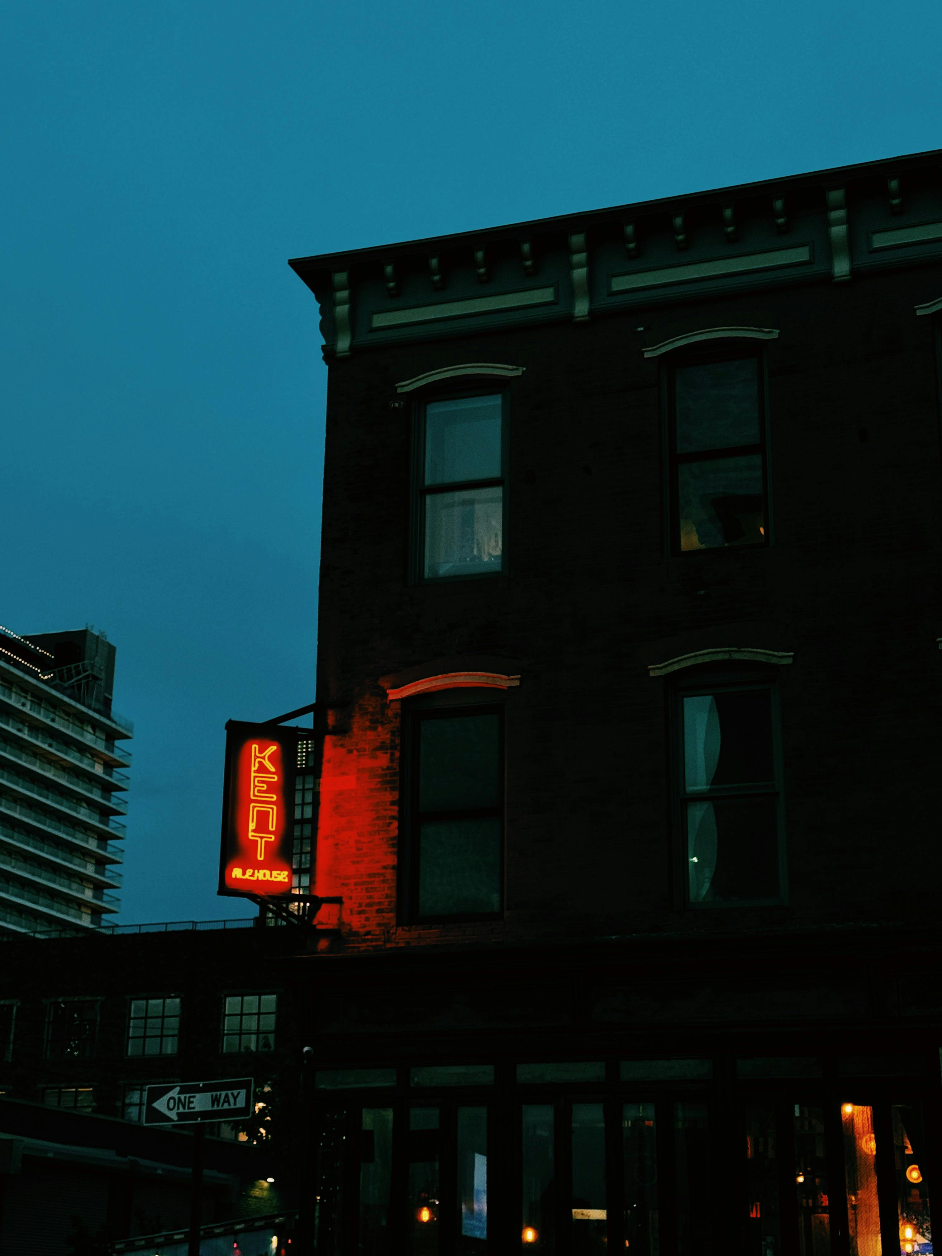 Single Neon Sign on Dark Tenement Building · Free Stock Photo