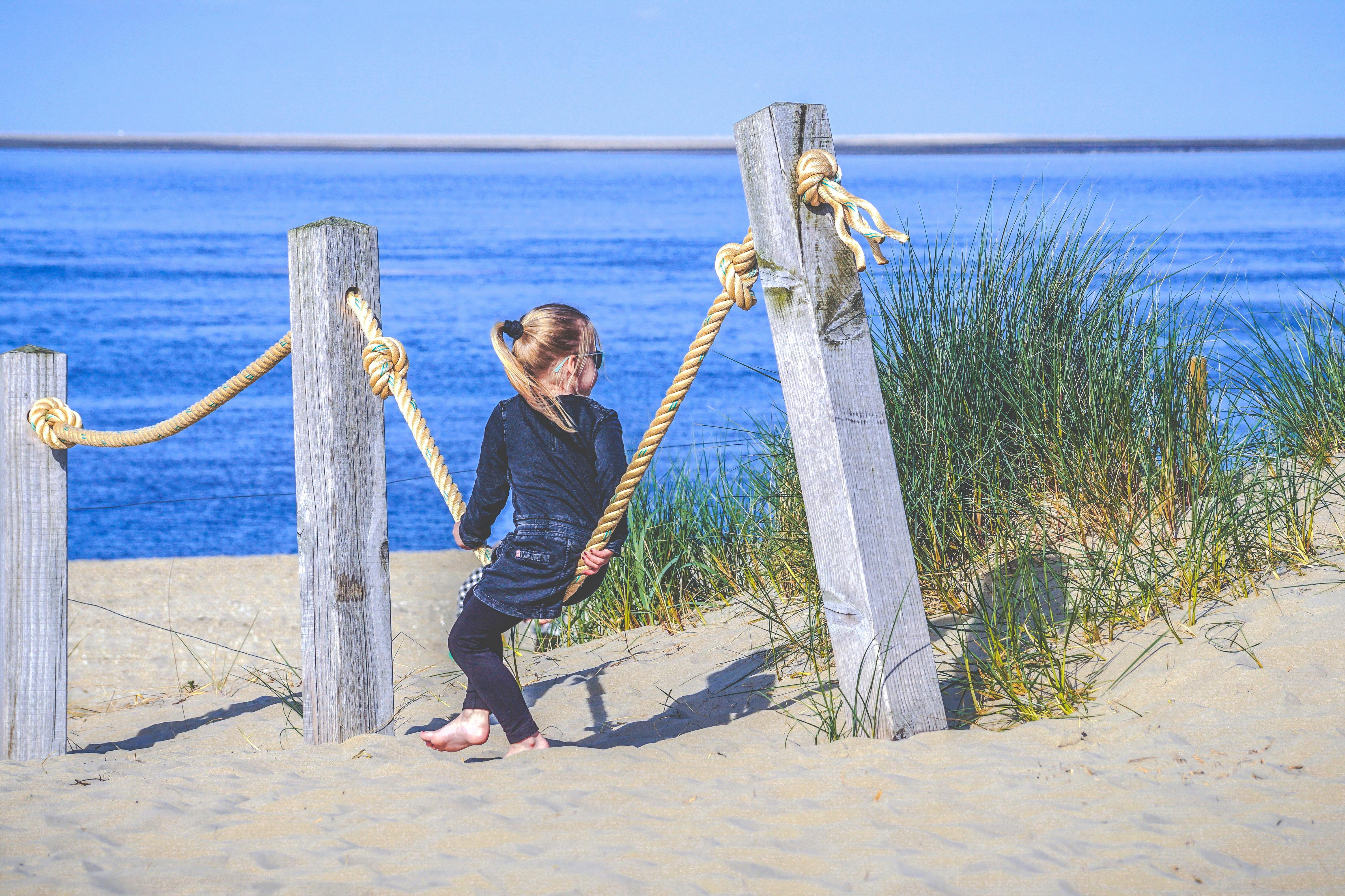 Girl Sitting On Rope At The Fence On Sand · Free Stock Photo