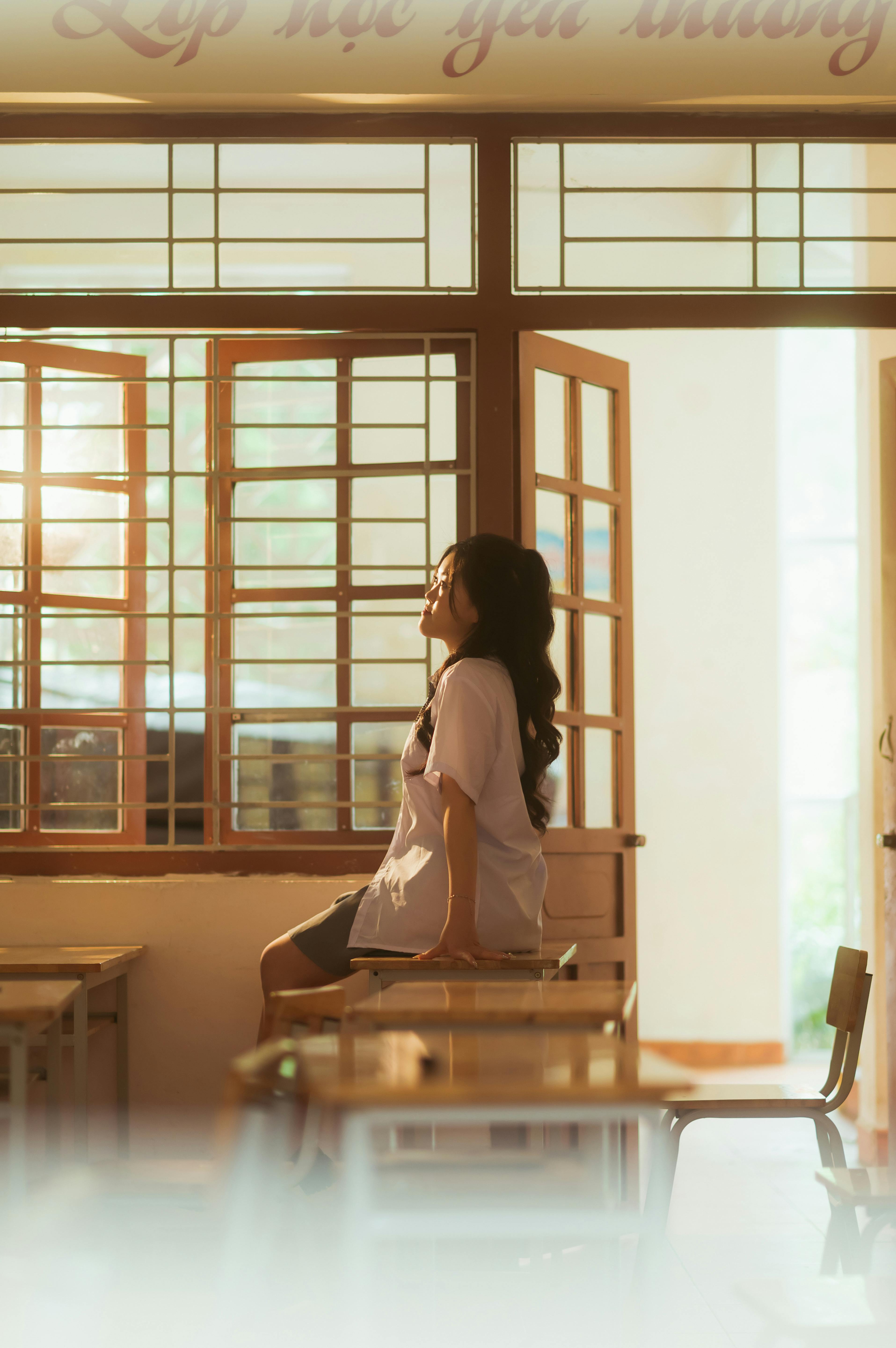 Side View of a Girl Sitting on the Desk in a Classroom · Free Stock Photo