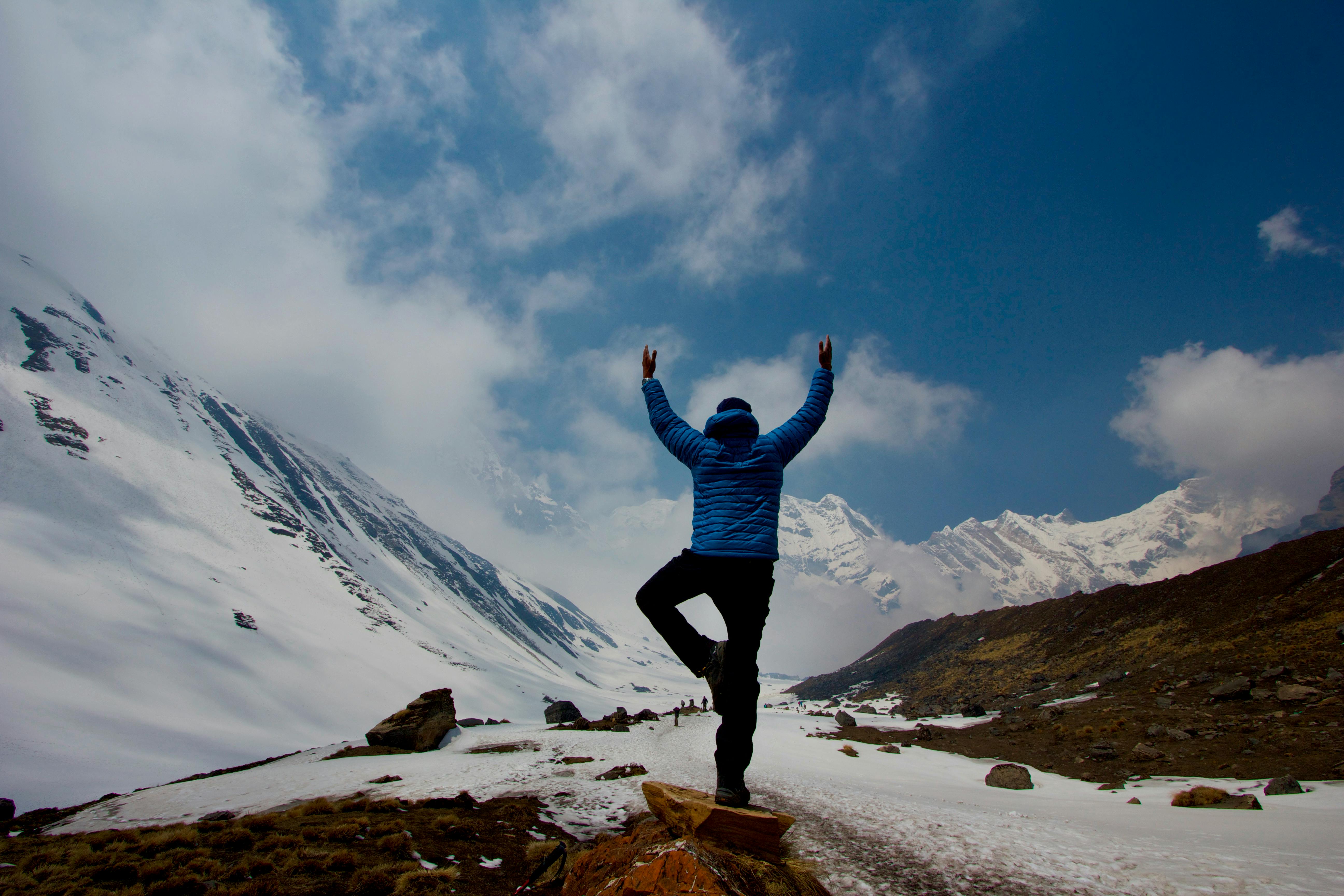 A person standing on one leg with arms raised overlooking the Annapurna ...